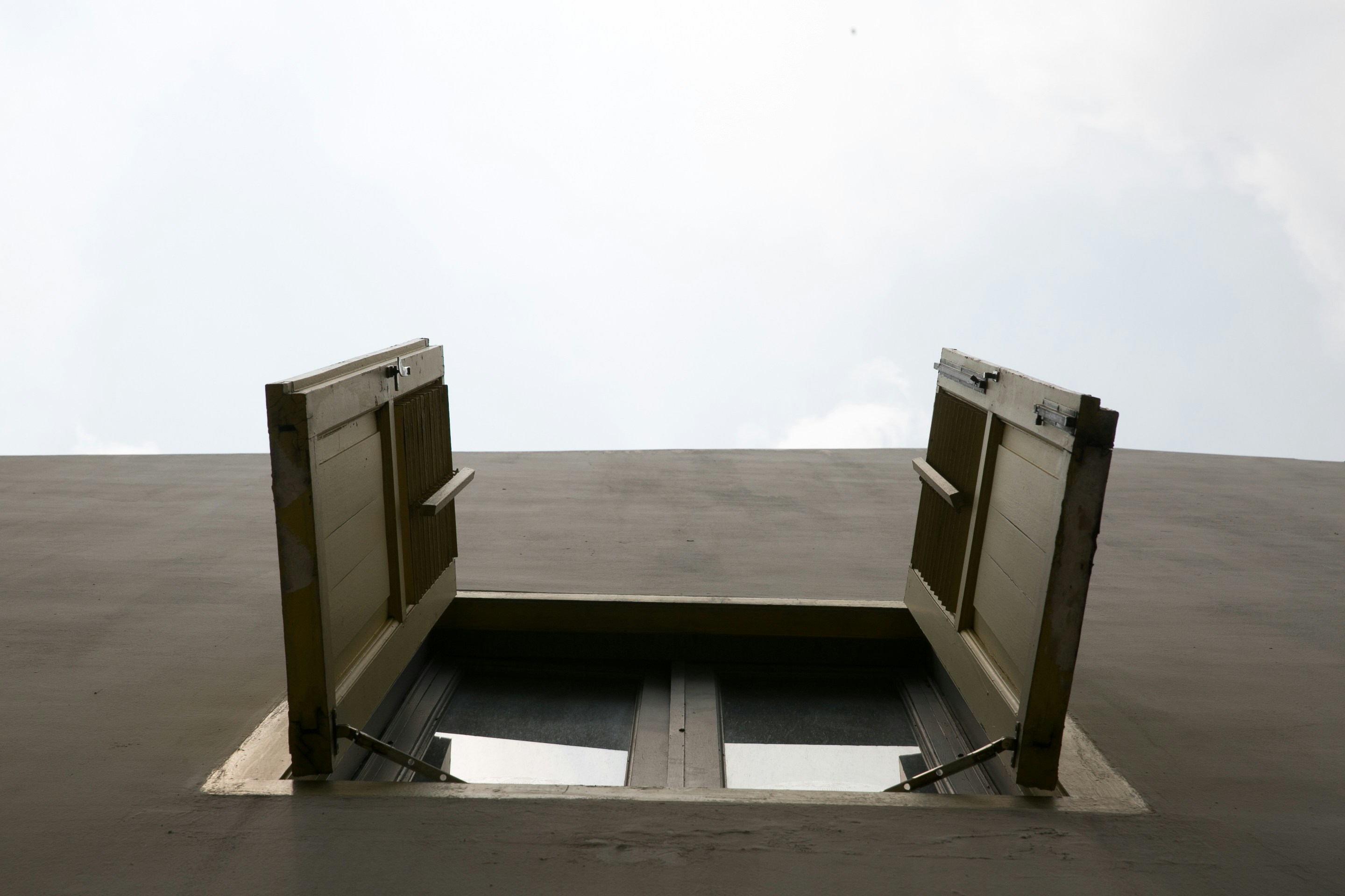 Open window with shutters ajar, framed against a cloudy sky, inviting a sense of freedom and exploration.