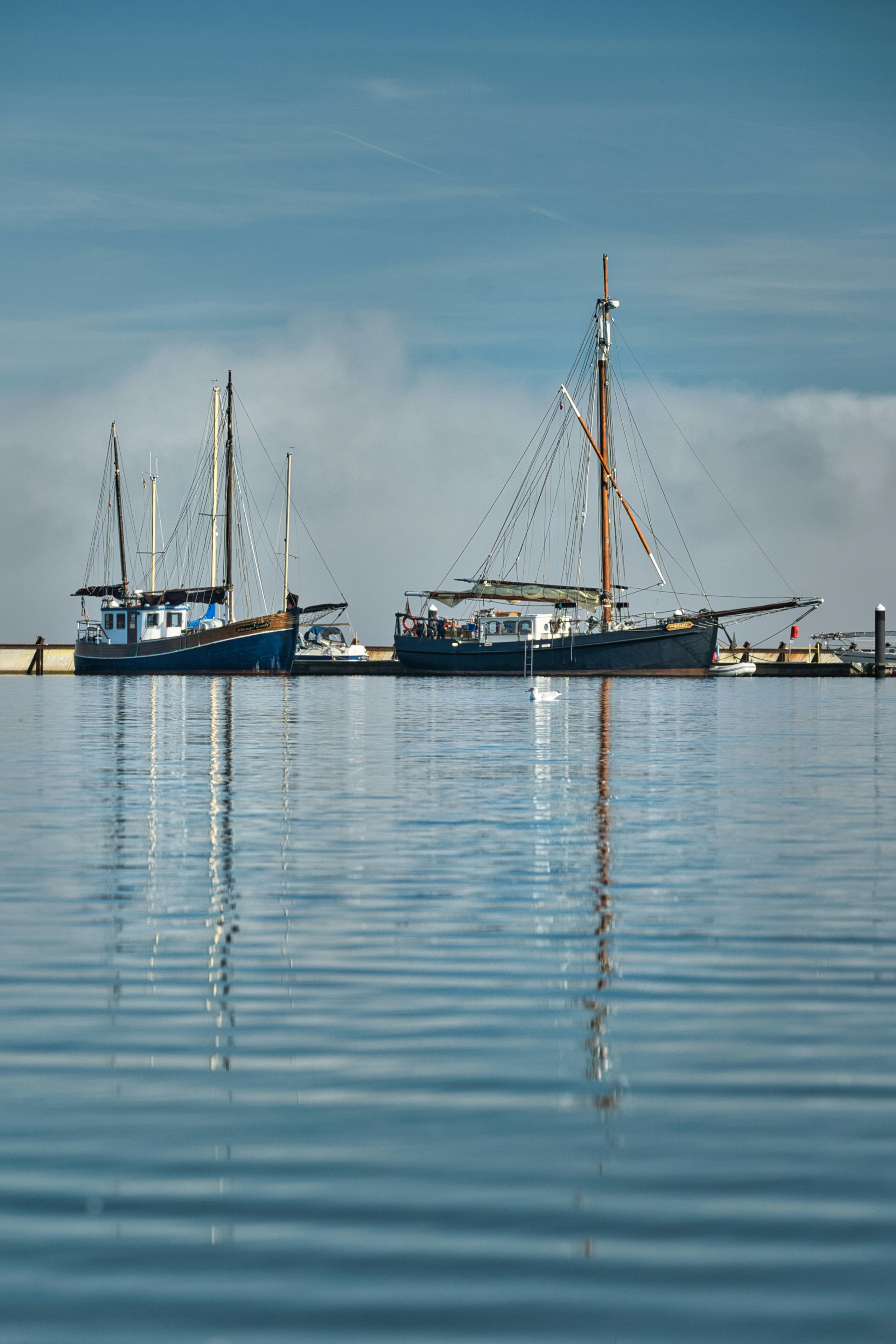 Two sailboats docked on a calm bay
