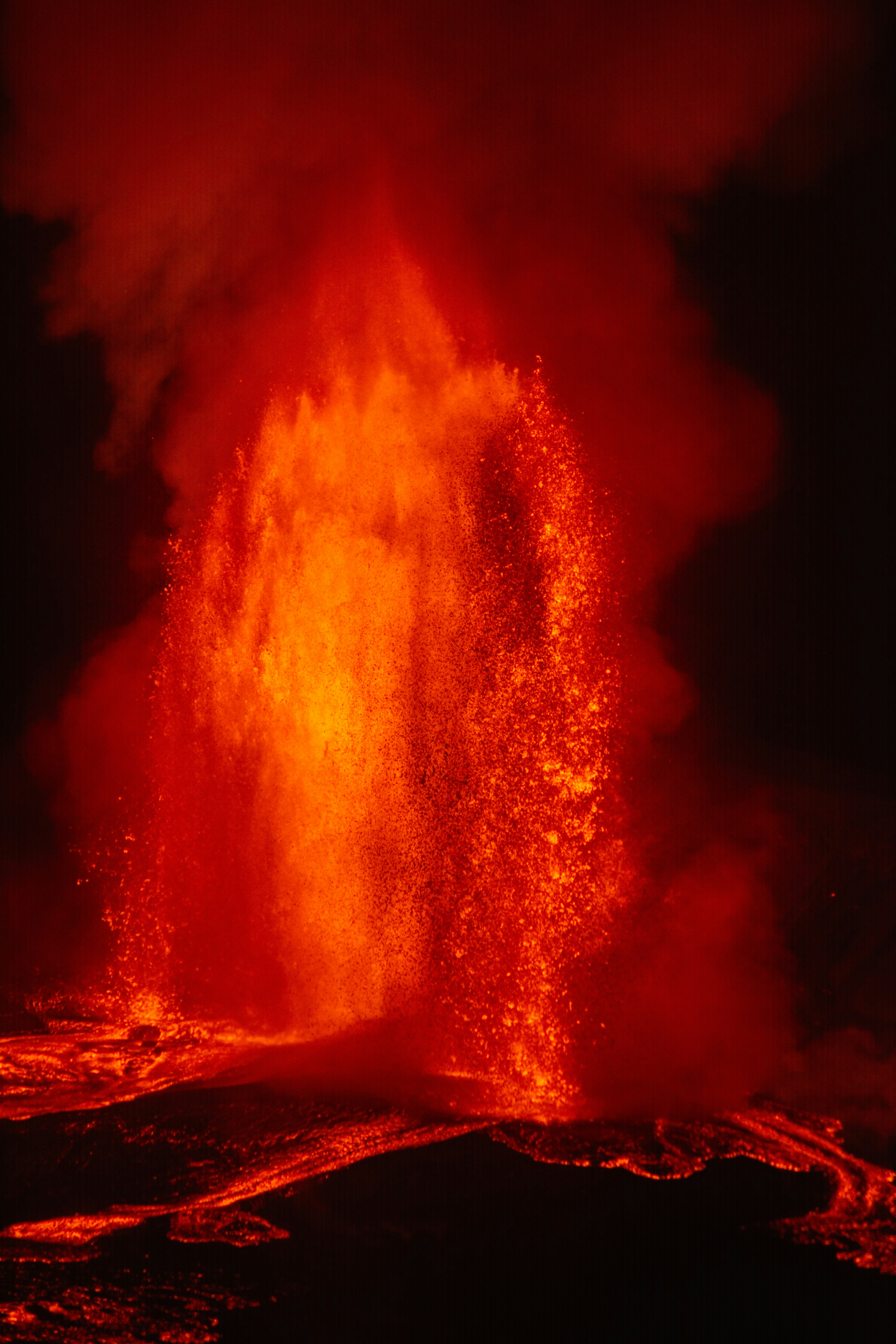 Volcanic eruption spewing molten lava and ash into the night sky, illuminating the surroundings with a brilliant glow.
