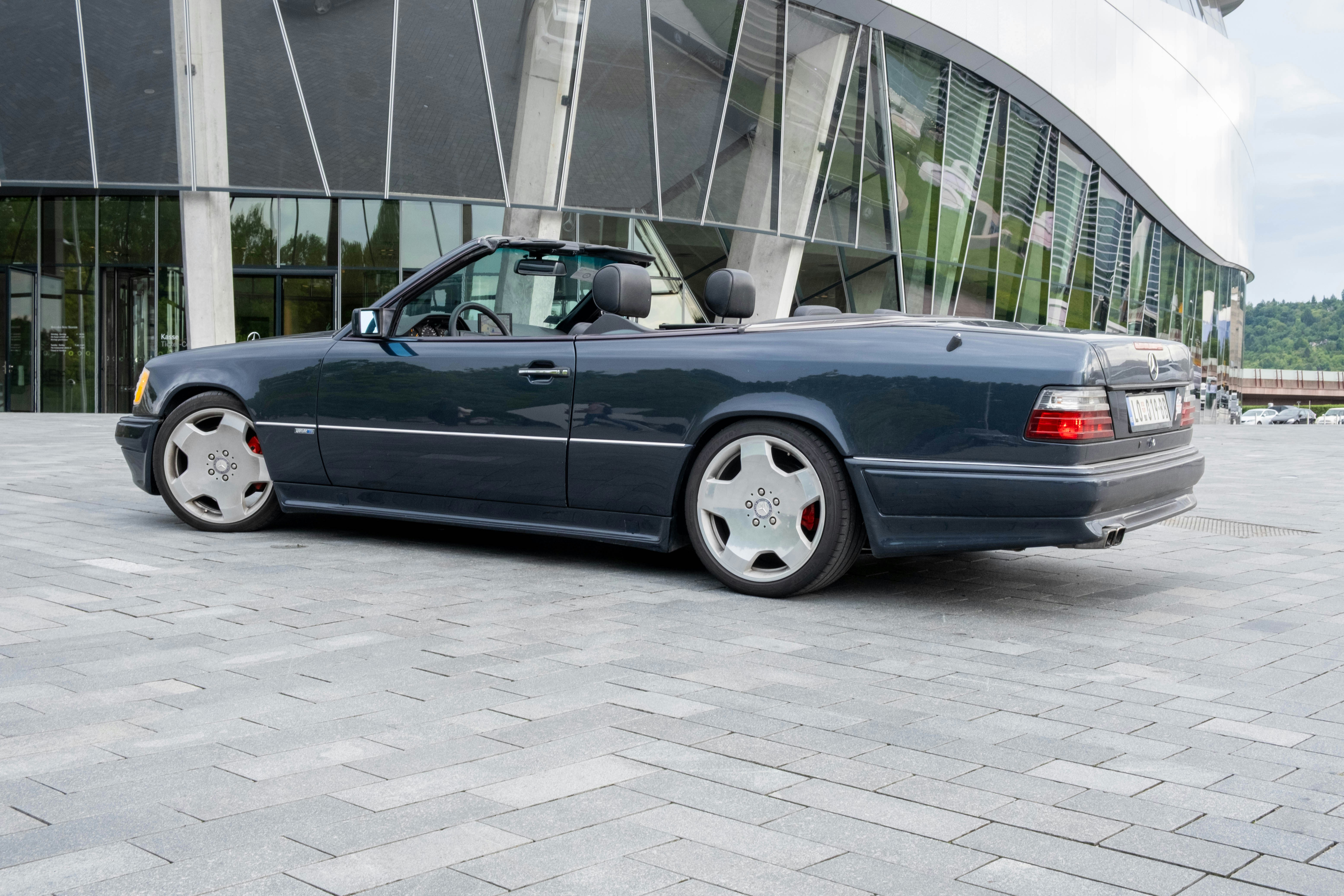 Low-Slung Blue Convertible Parked Against a Glassy Urban Curve