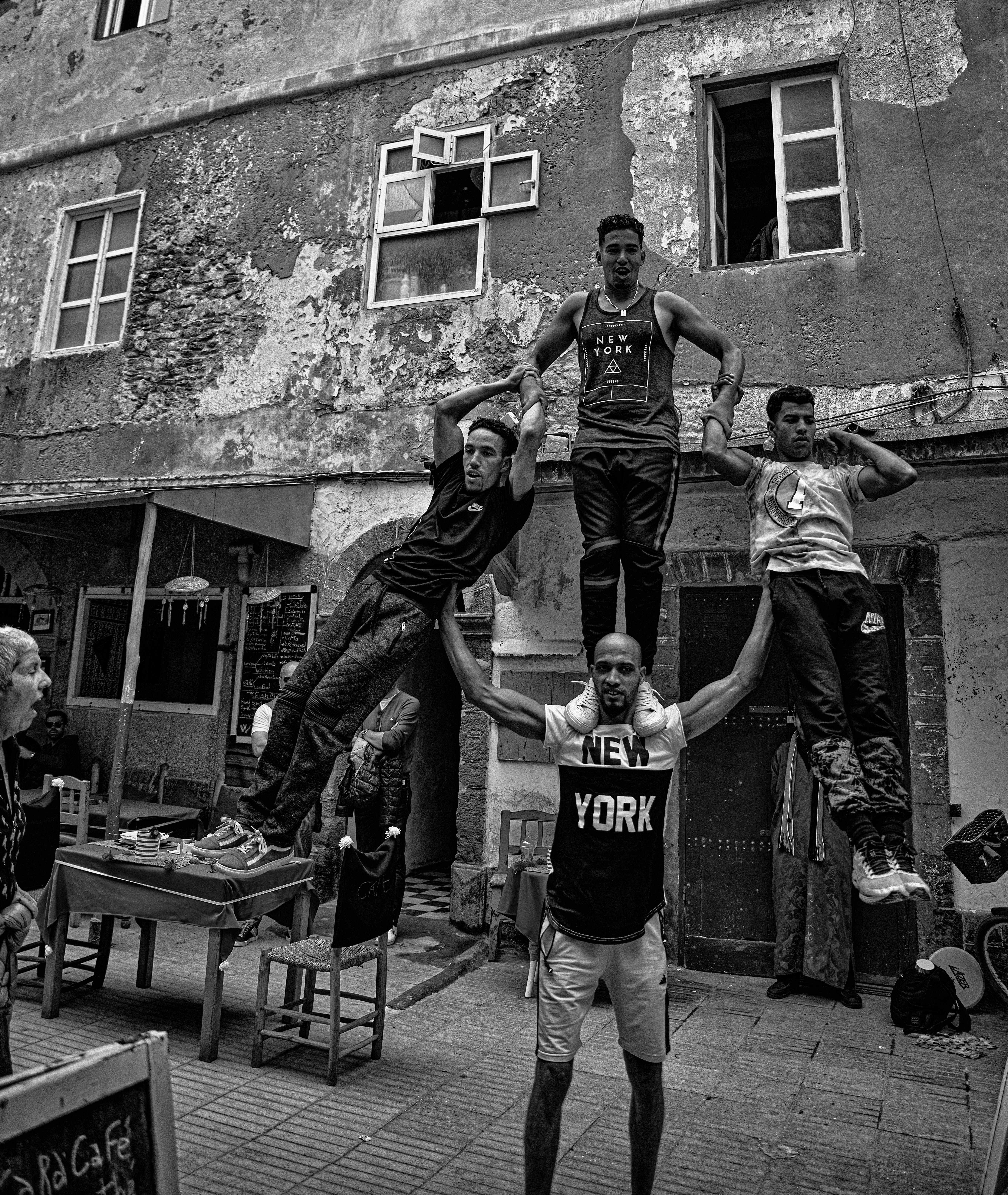 Four men form a human pyramid in an alleyway