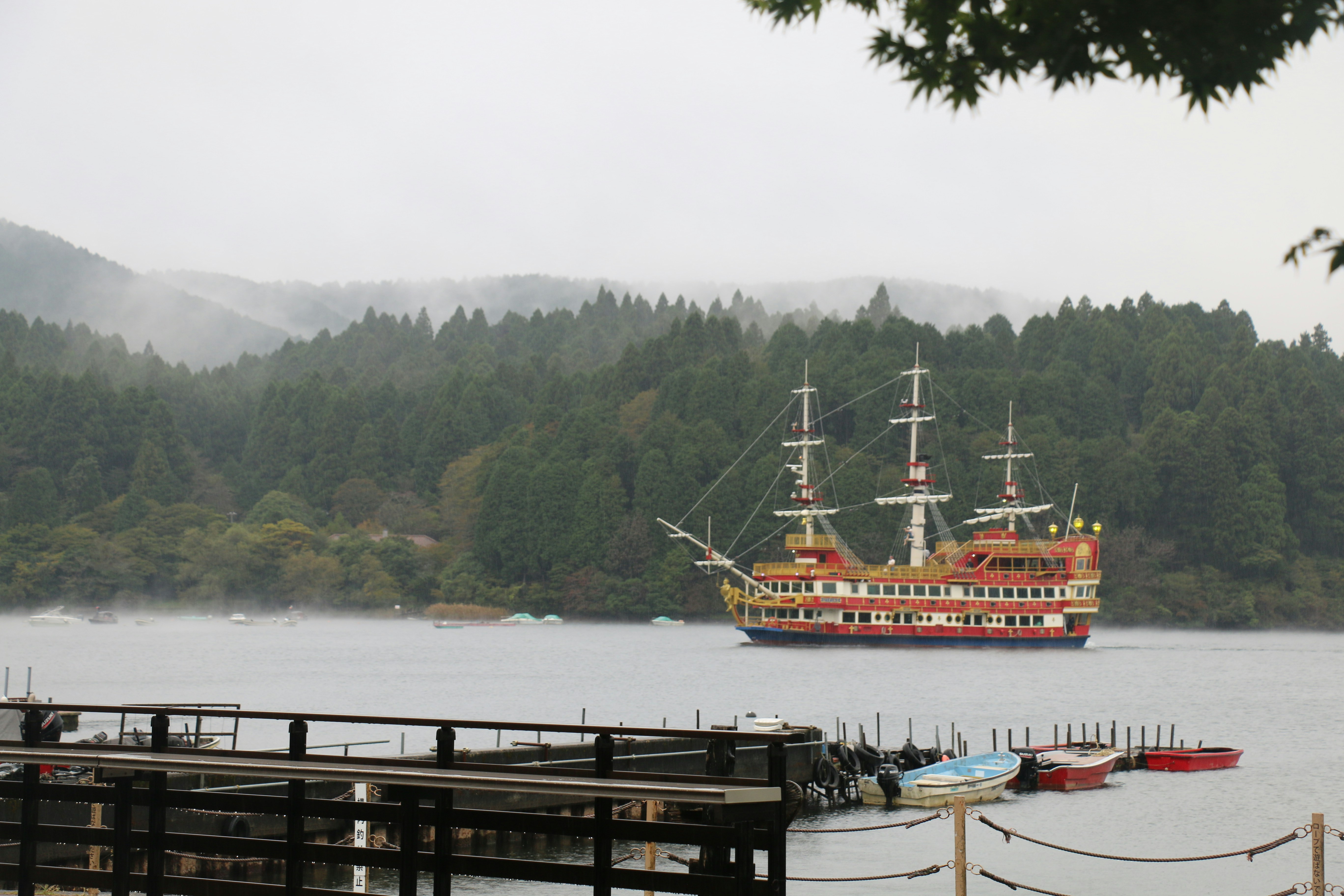 A large pirate ship sails on a misty lake.