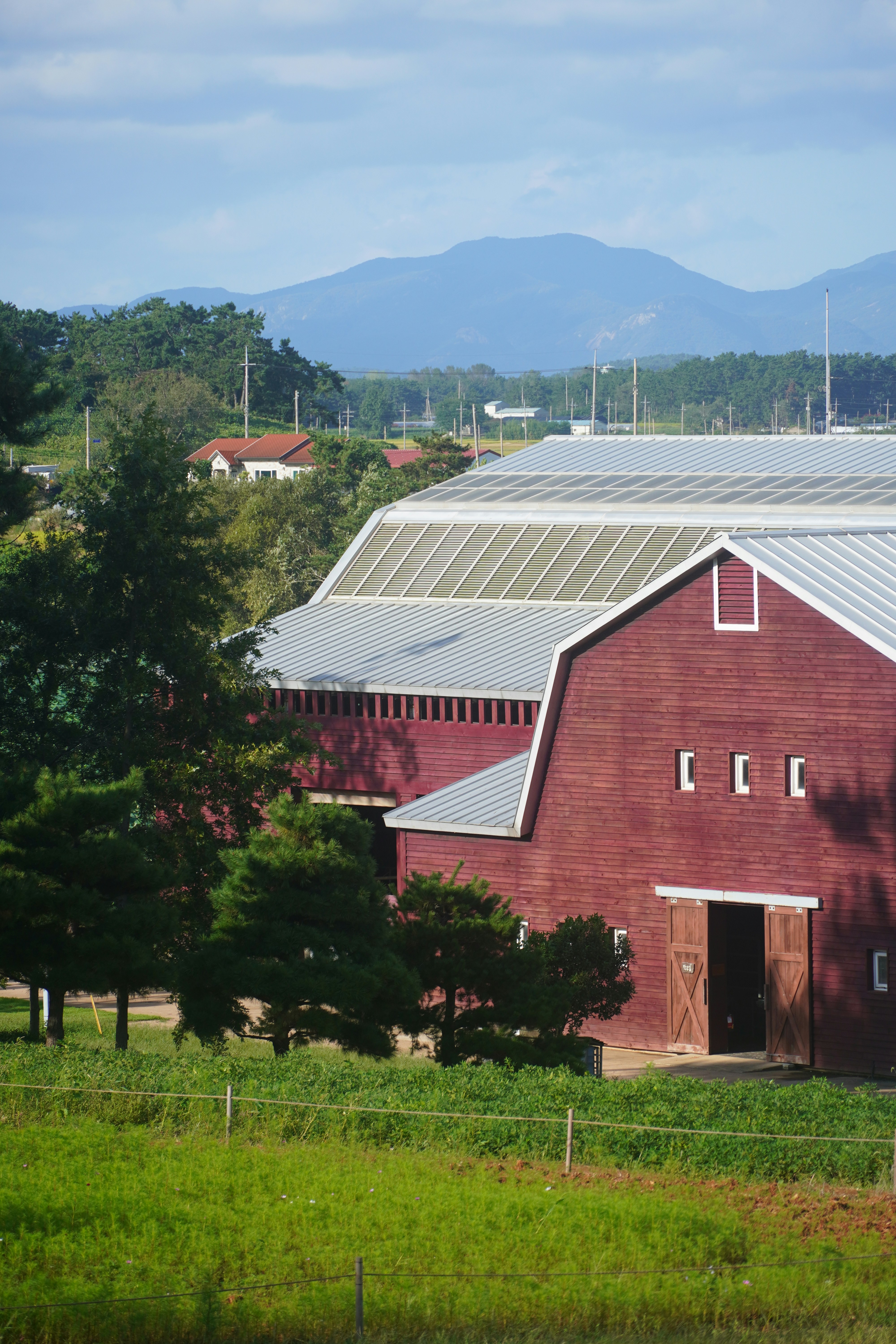 Sunlit Red Barn Framed by Fields and Distant Mountains