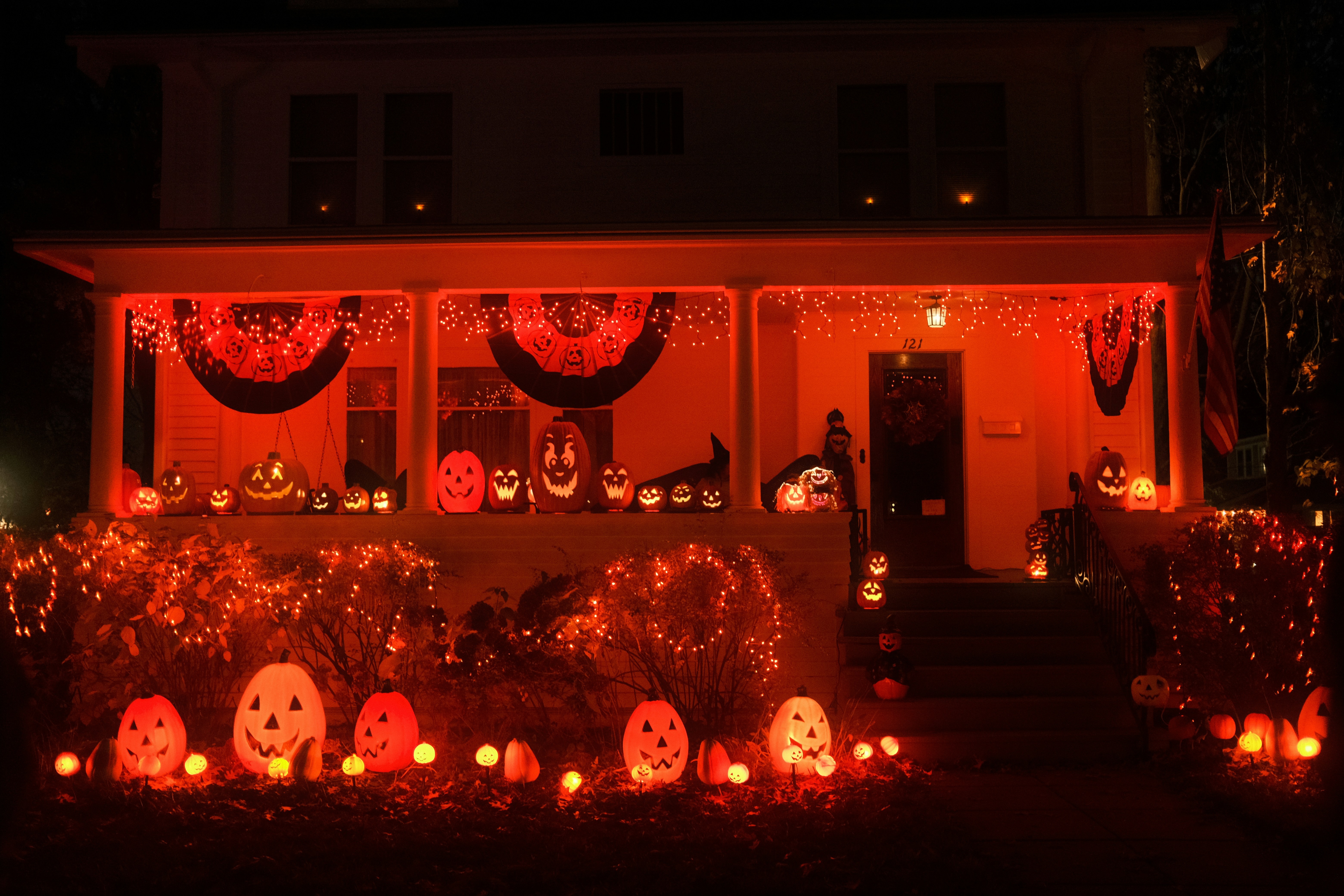 A festively decorated porch adorned with glowing jack-o'-lanterns and vibrant lights, creating a spooky yet inviting atmosphere for Halloween.
