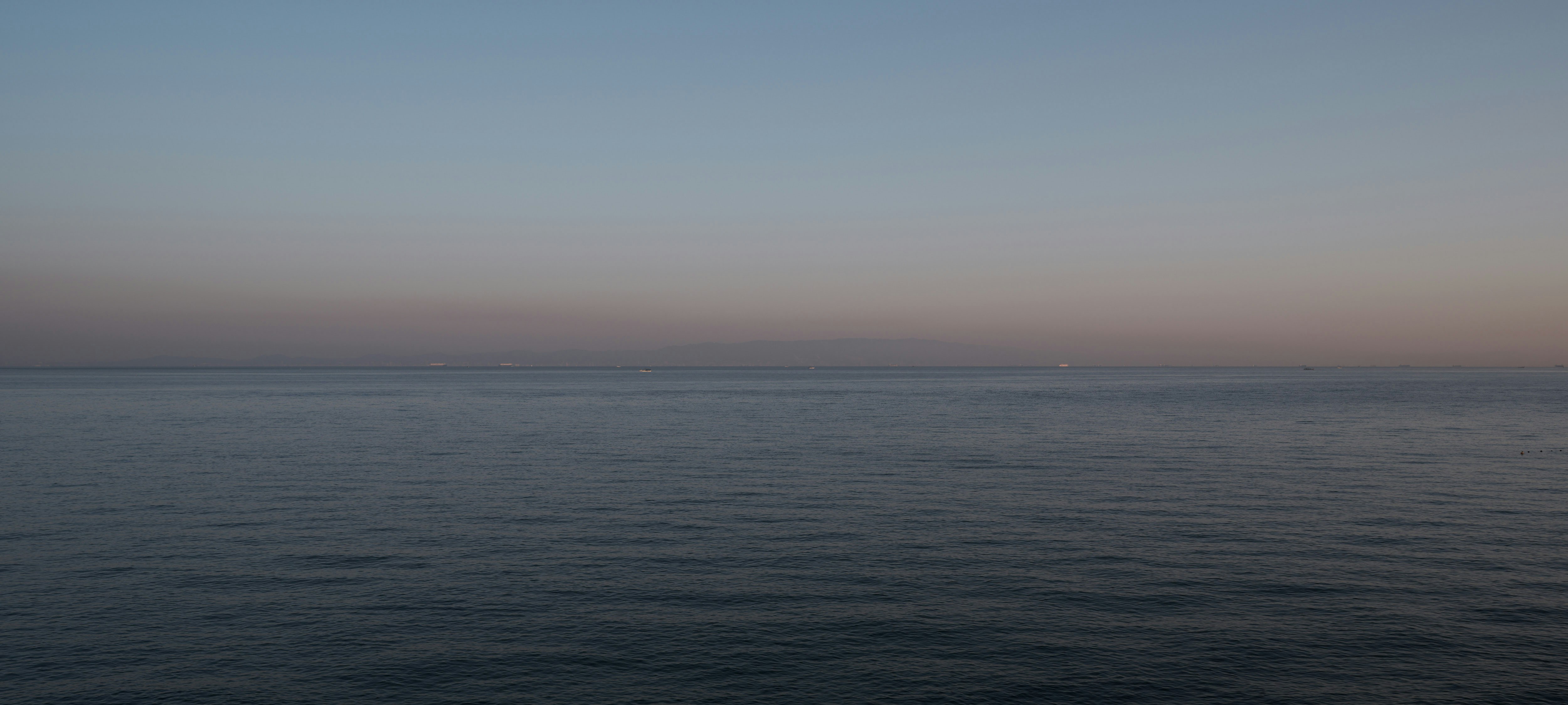 Osaka Bay in the Morning, taken from Izumisano. | Calm ocean horizon at dusk with soft sky colors