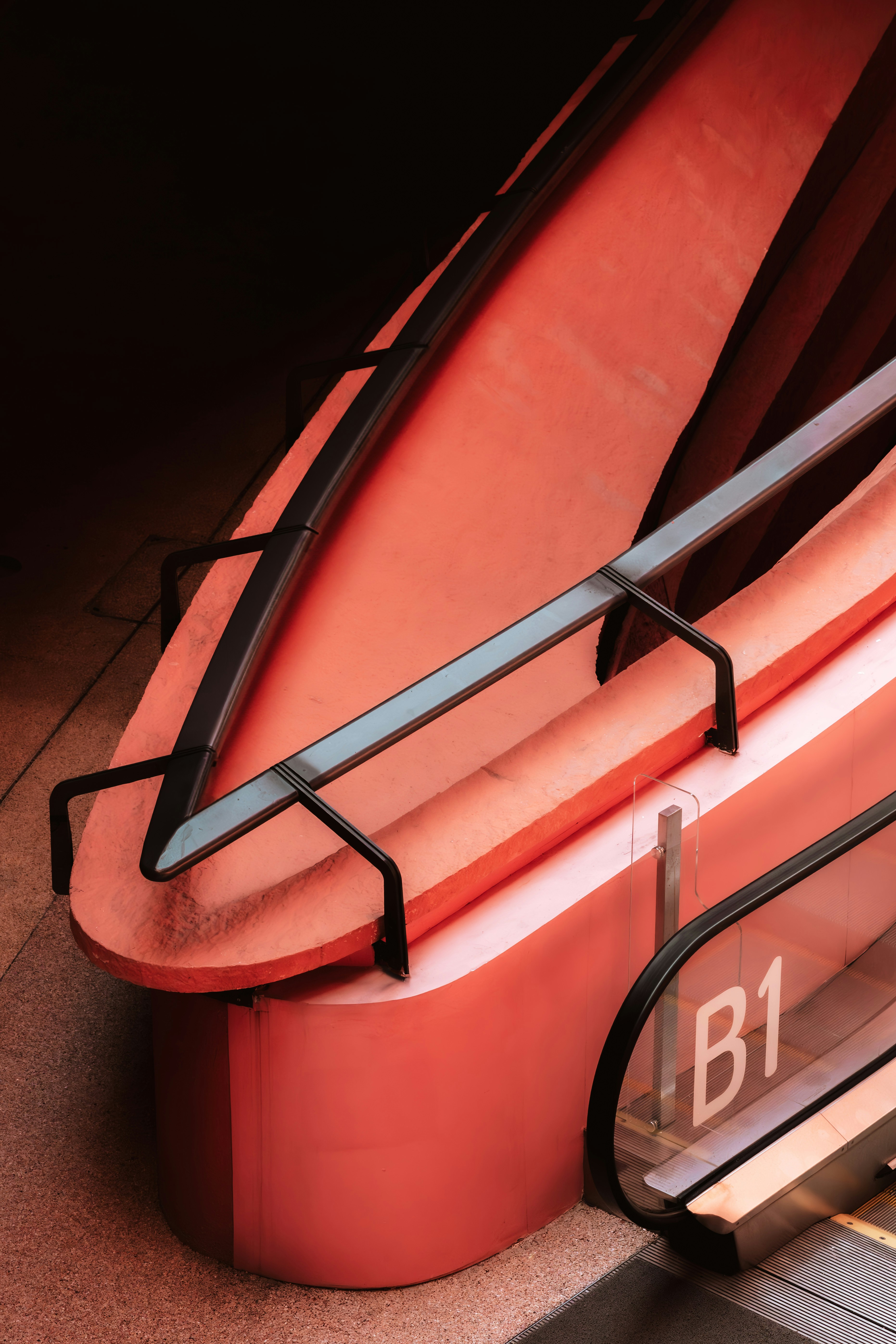 Stylish red staircase with sleek black railings in a modern architectural setting.