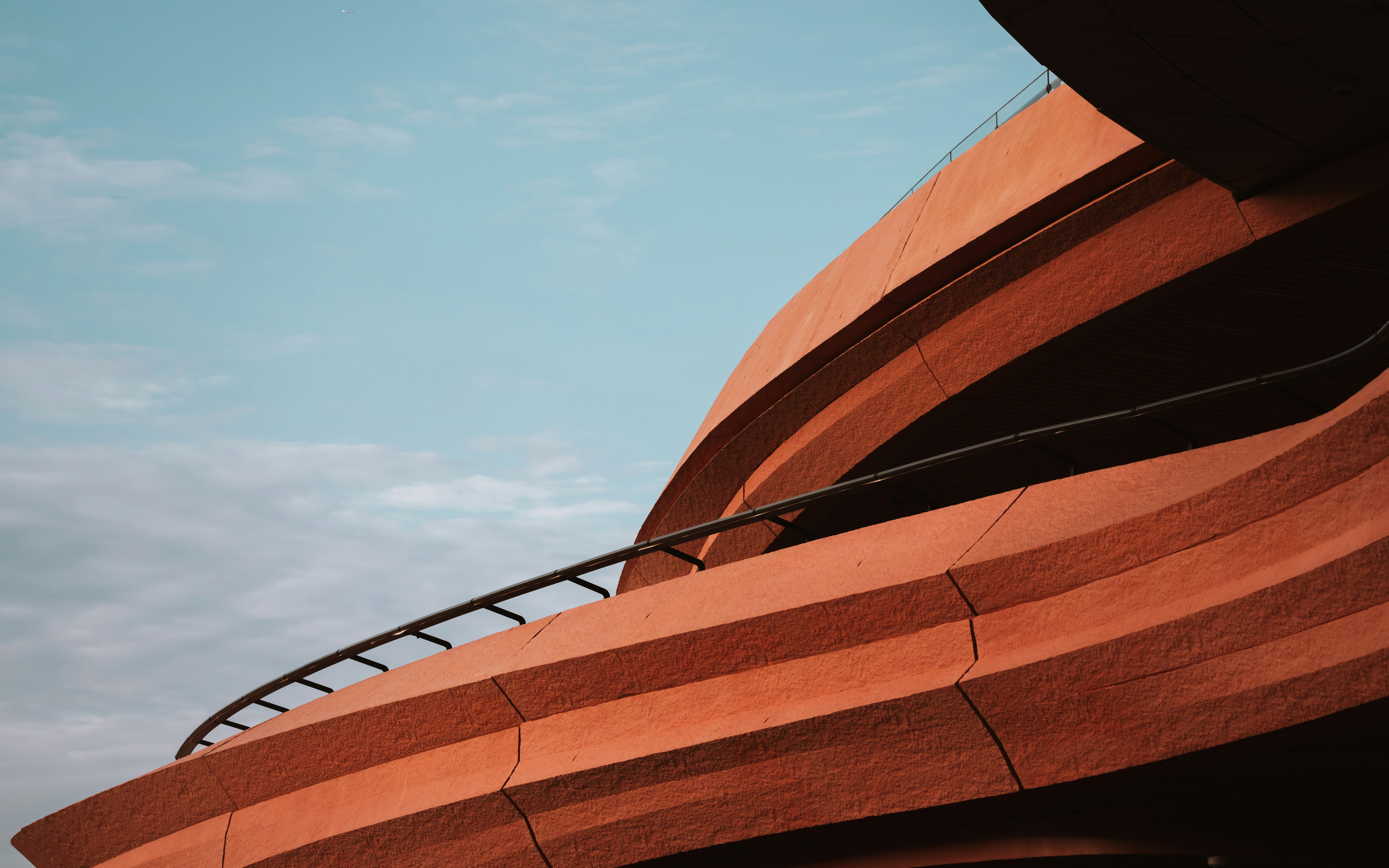 Curving terracotta facade against a blue sky