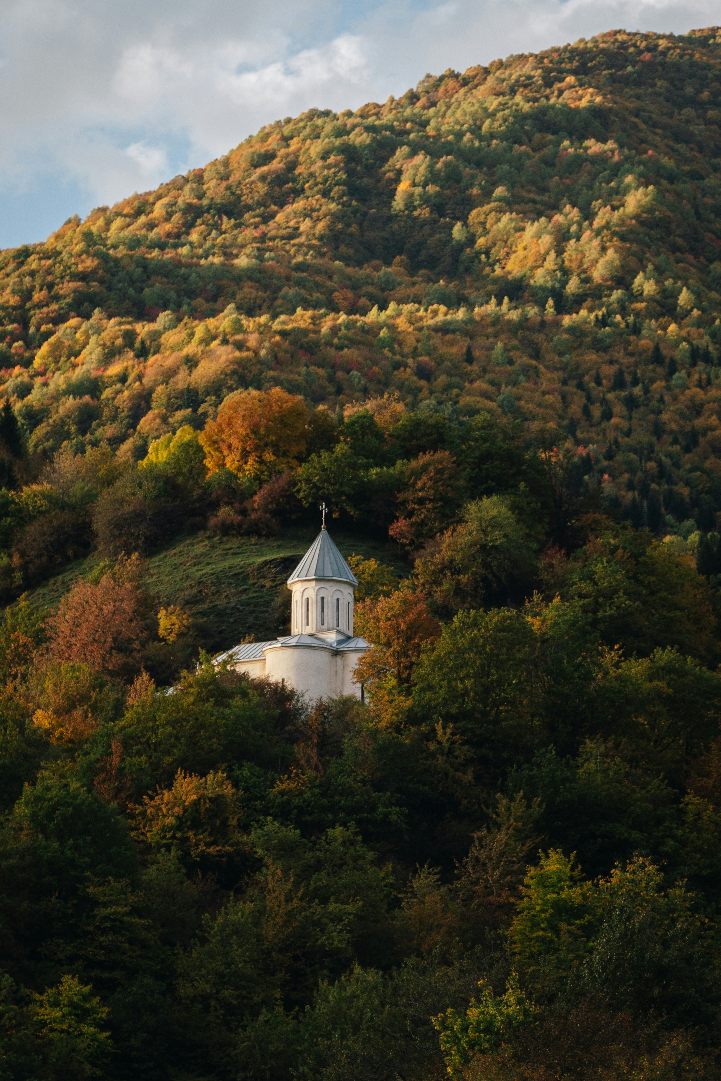 White church nestled in colorful autumn forest