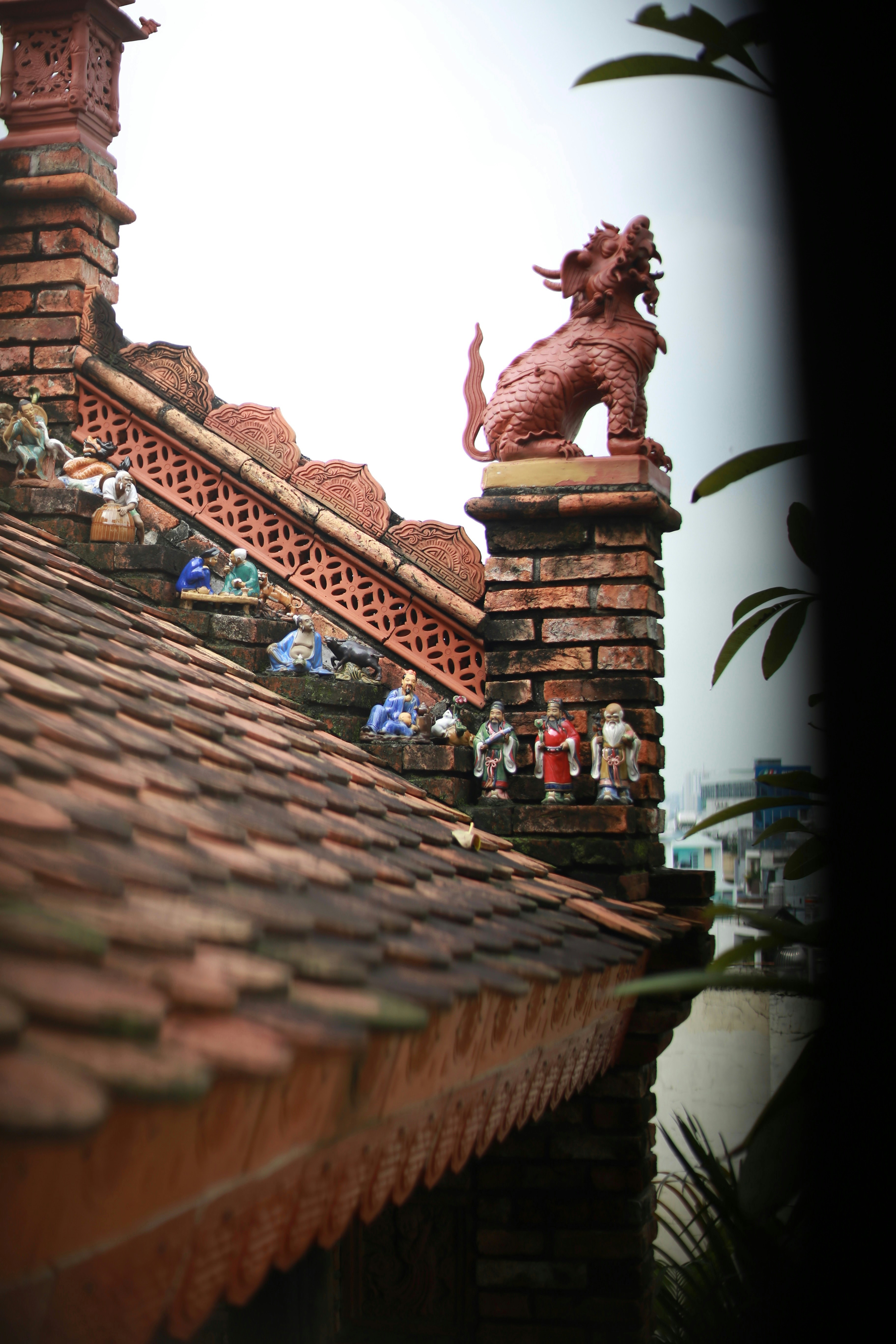 Dragon guardian on tiled eave under a narrow skyline