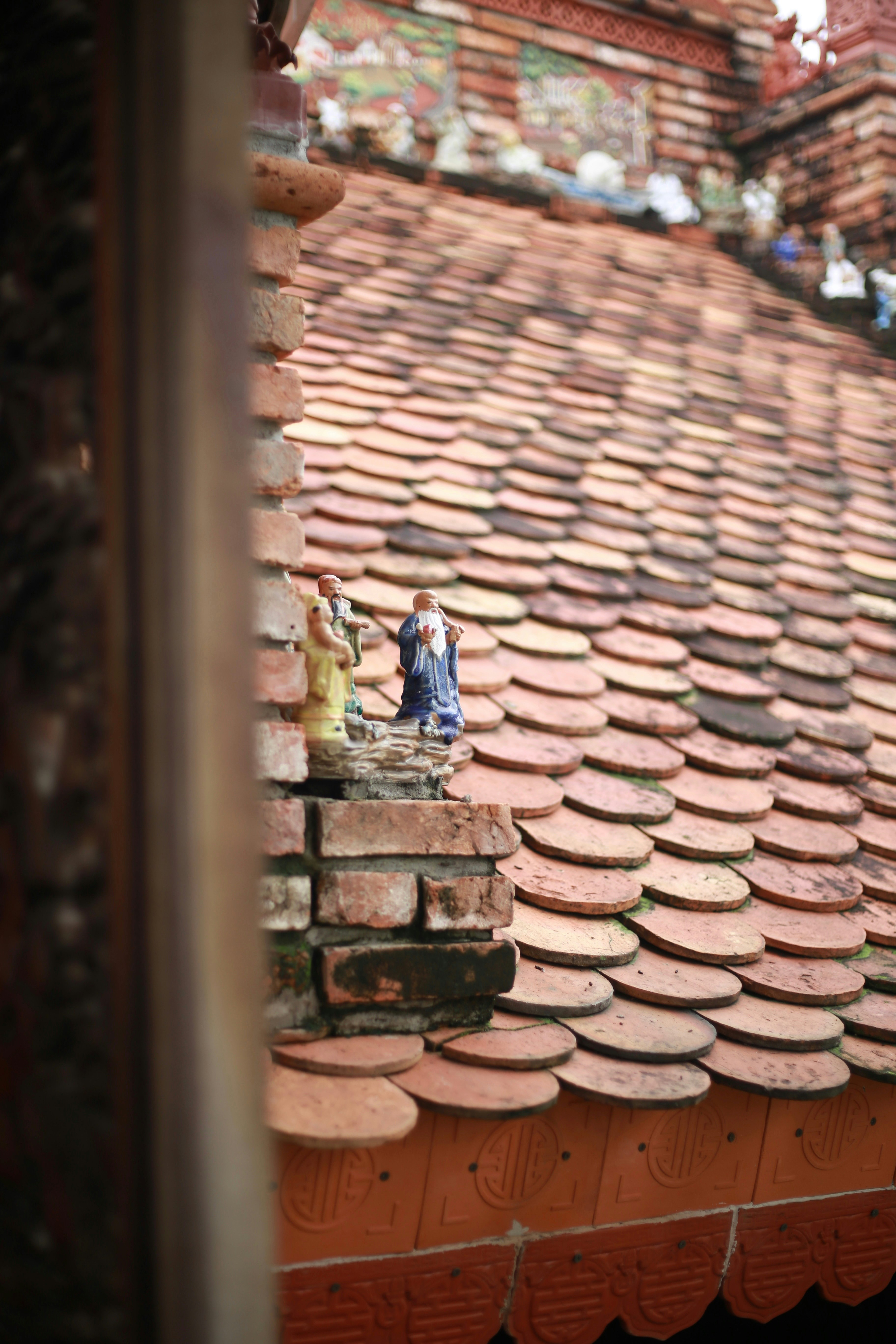 Miniature Monks on a Red-Tiled Temple Roof