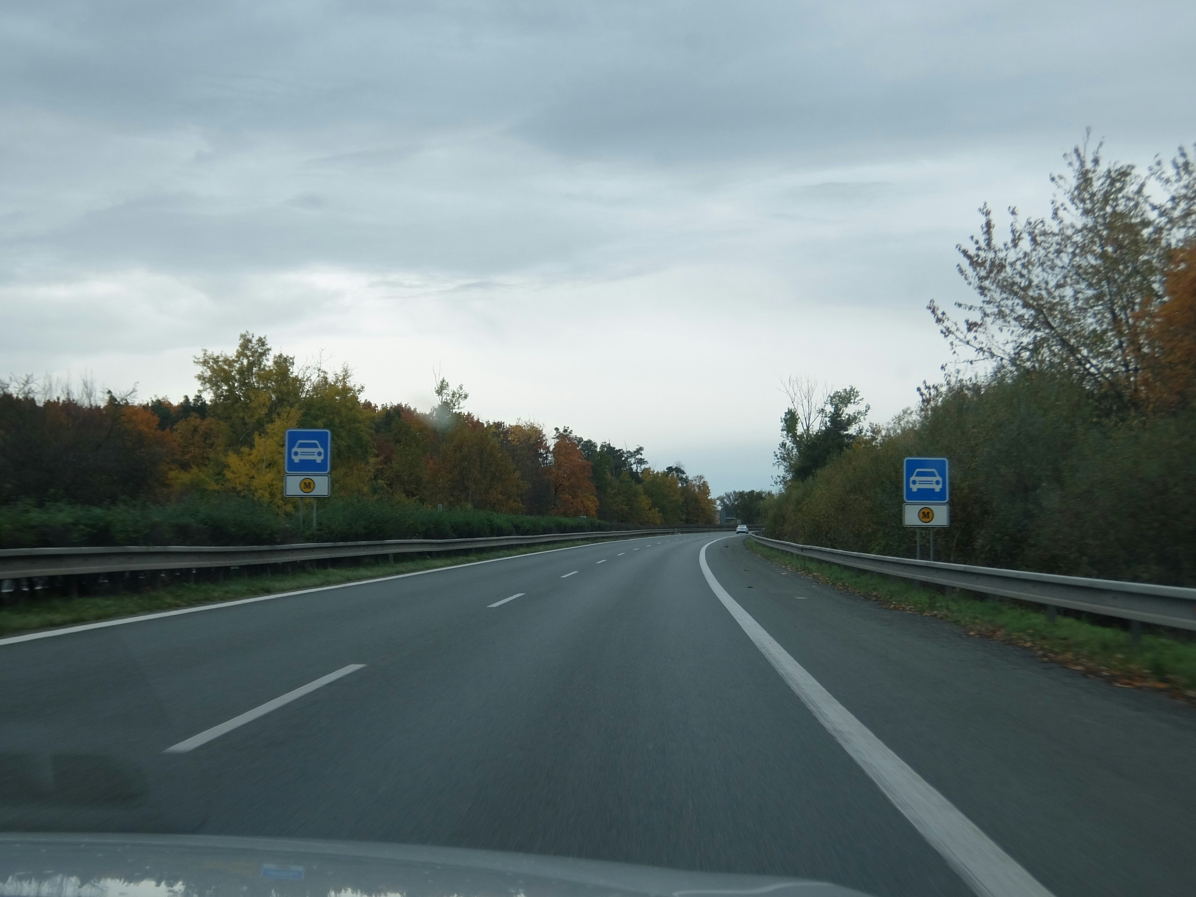 Highway with autumn trees and road signs