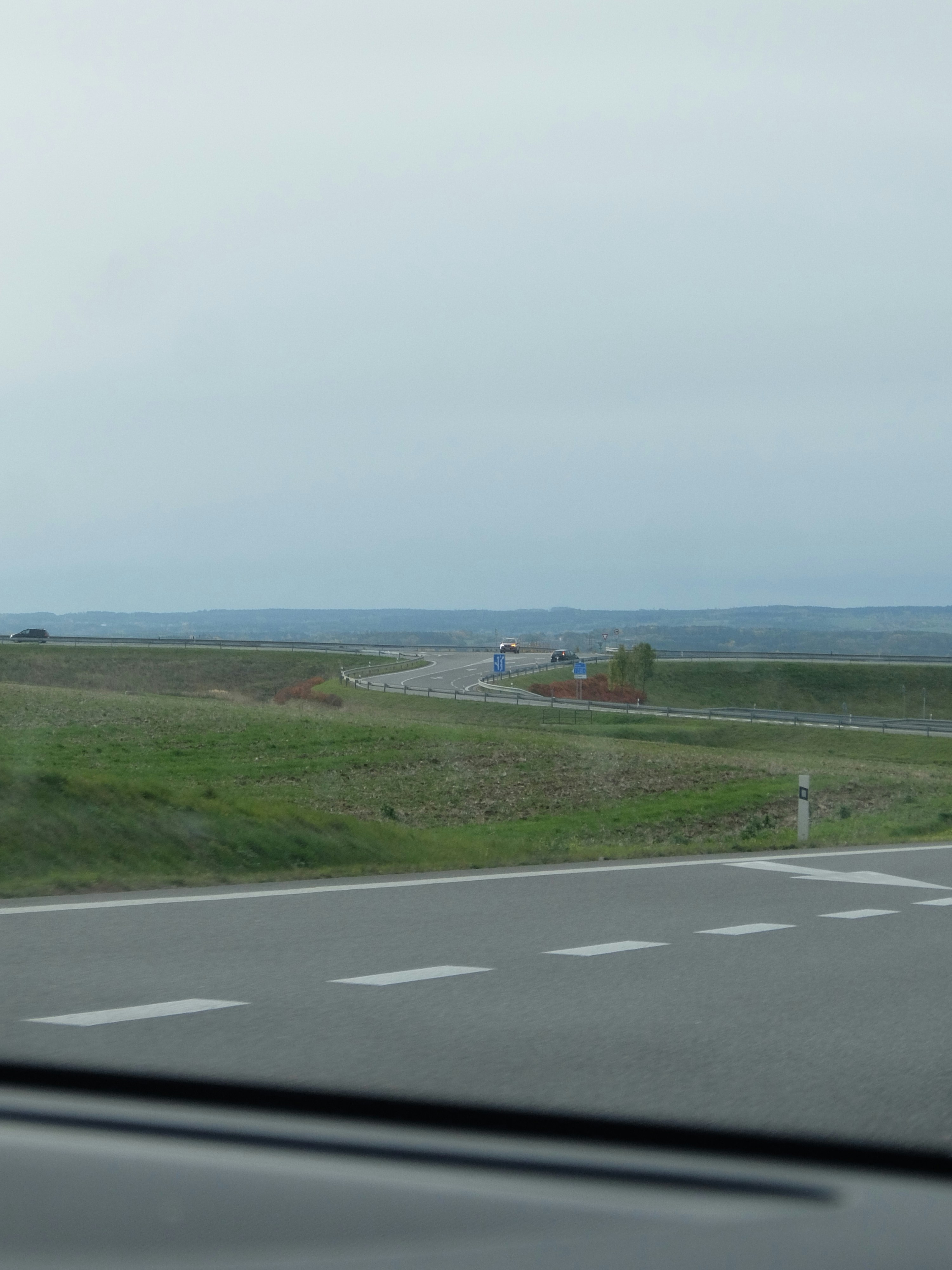 Road curving through green fields under a cloudy sky
