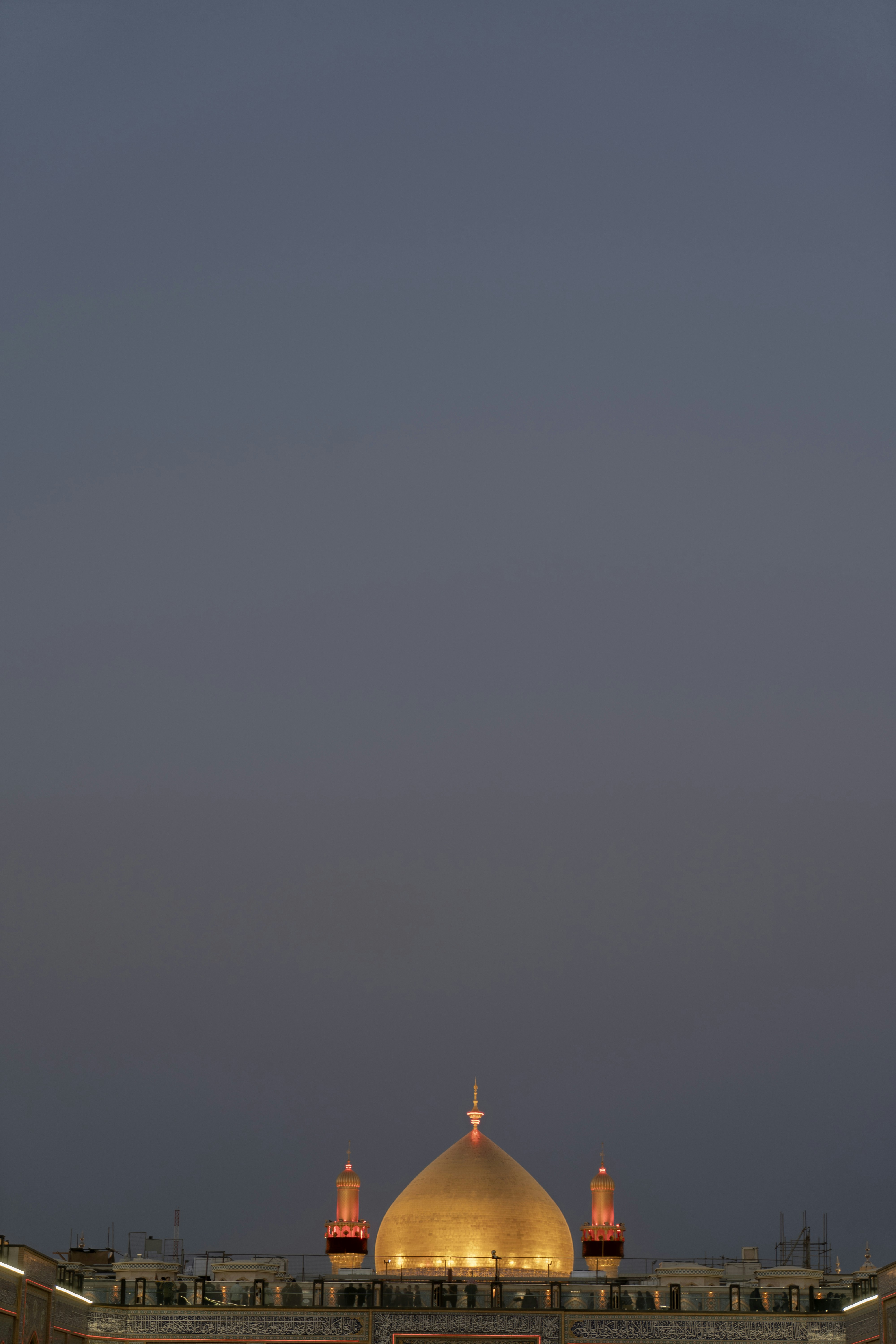 Golden dome of a mosque illuminated against a twilight sky, showcasing intricate architectural details and serene ambiance.