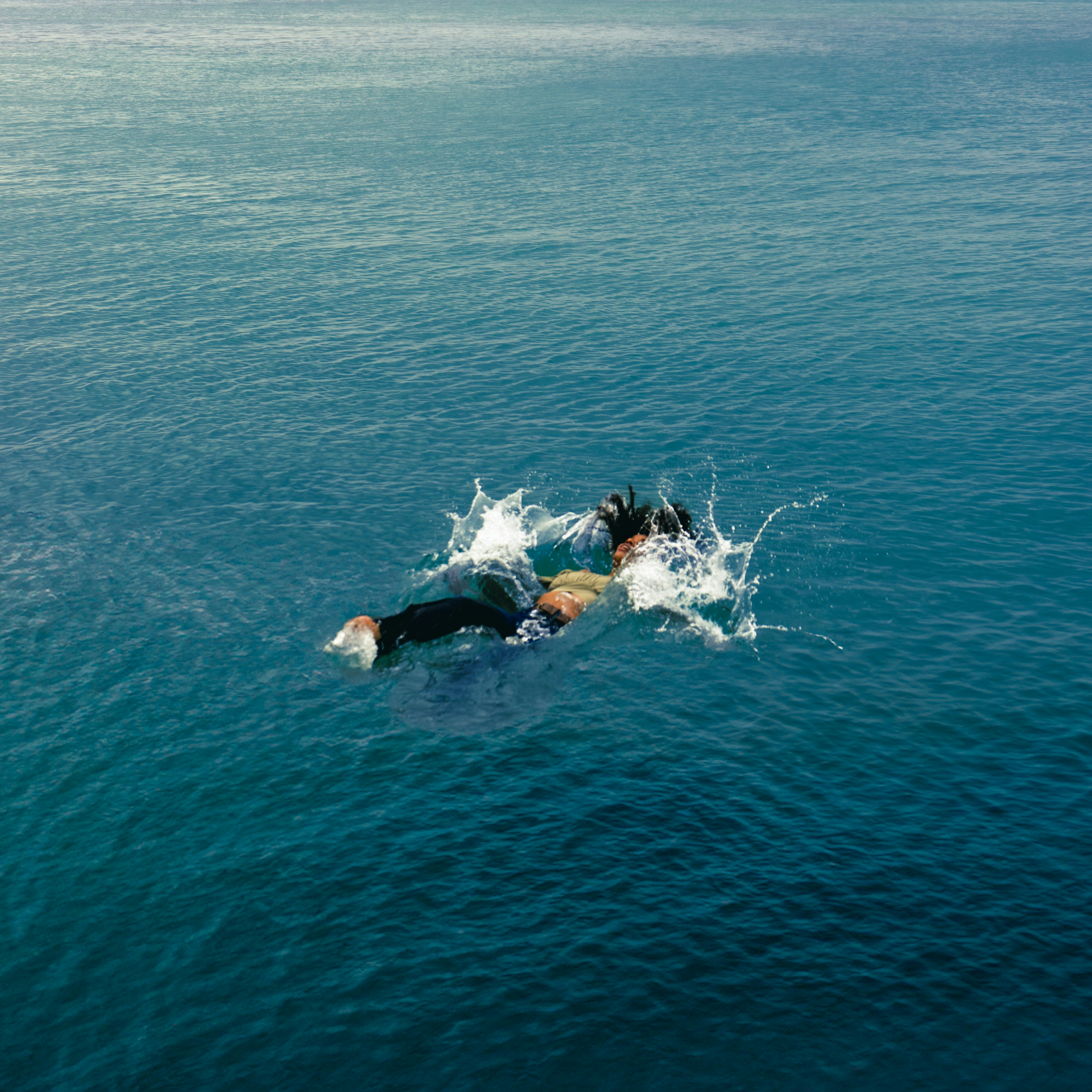 This is the cover of Venythia's album "We get it", she got in the water in Étretat, France, by 6° Celsius multiple times until we got the perfect shot. | Person swimming in the vast blue ocean water