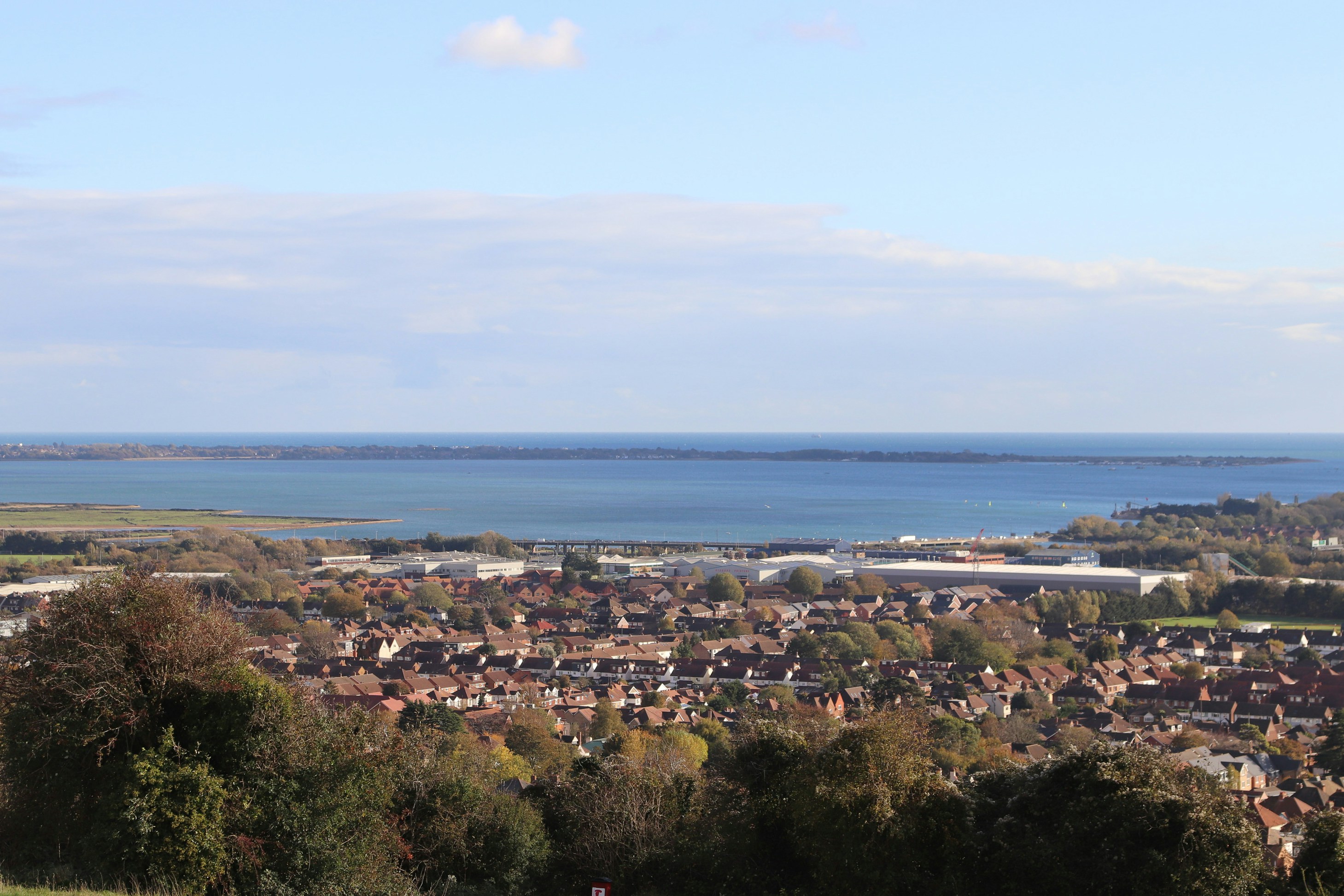 A panoramic view of a coastal town with shimmering waters and a clear sky, showcasing the blend of urban and natural landscapes.