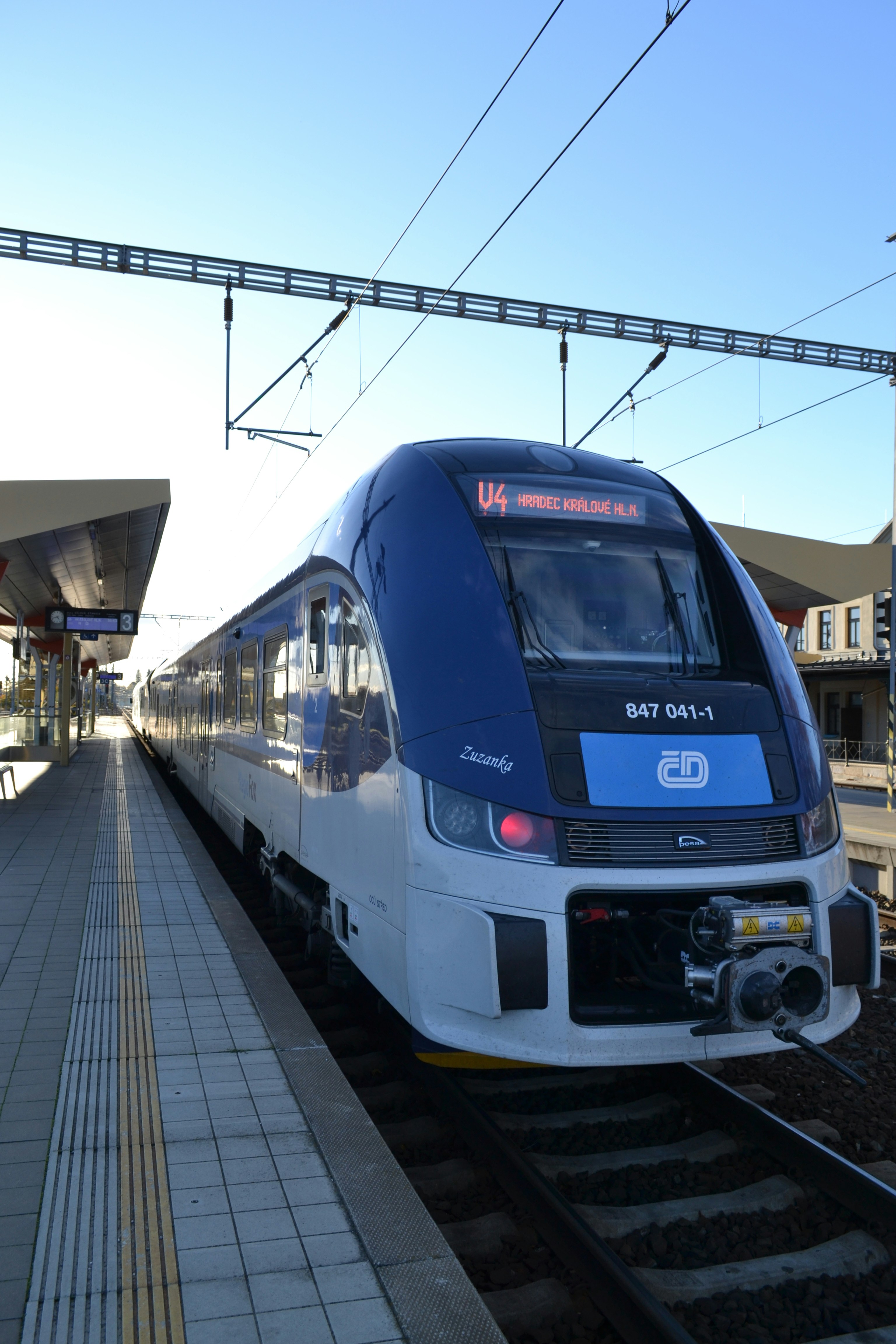 Modern blue and white train at station platform.