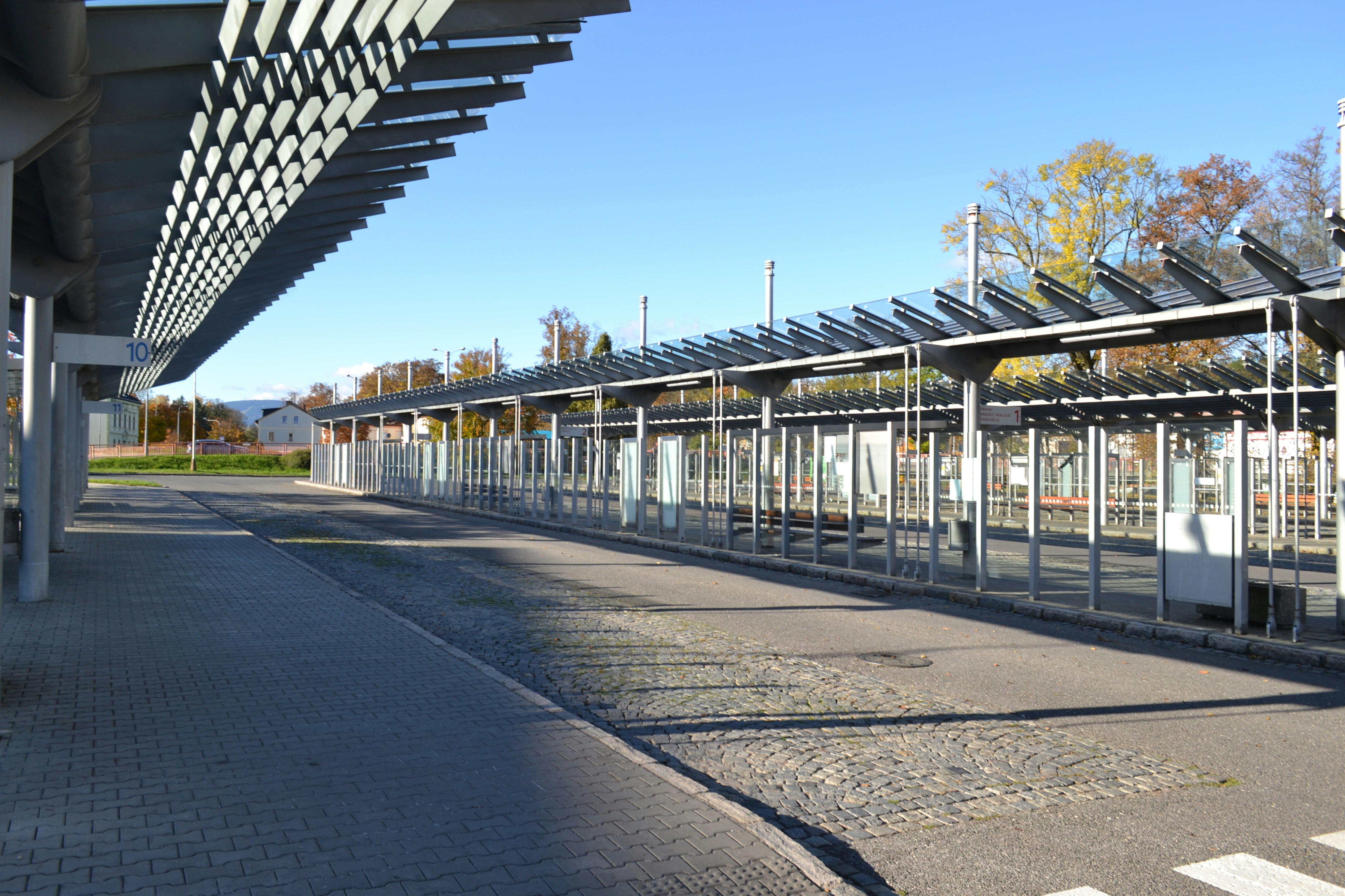 Modern bus stop shelter with glass panels and metal roof