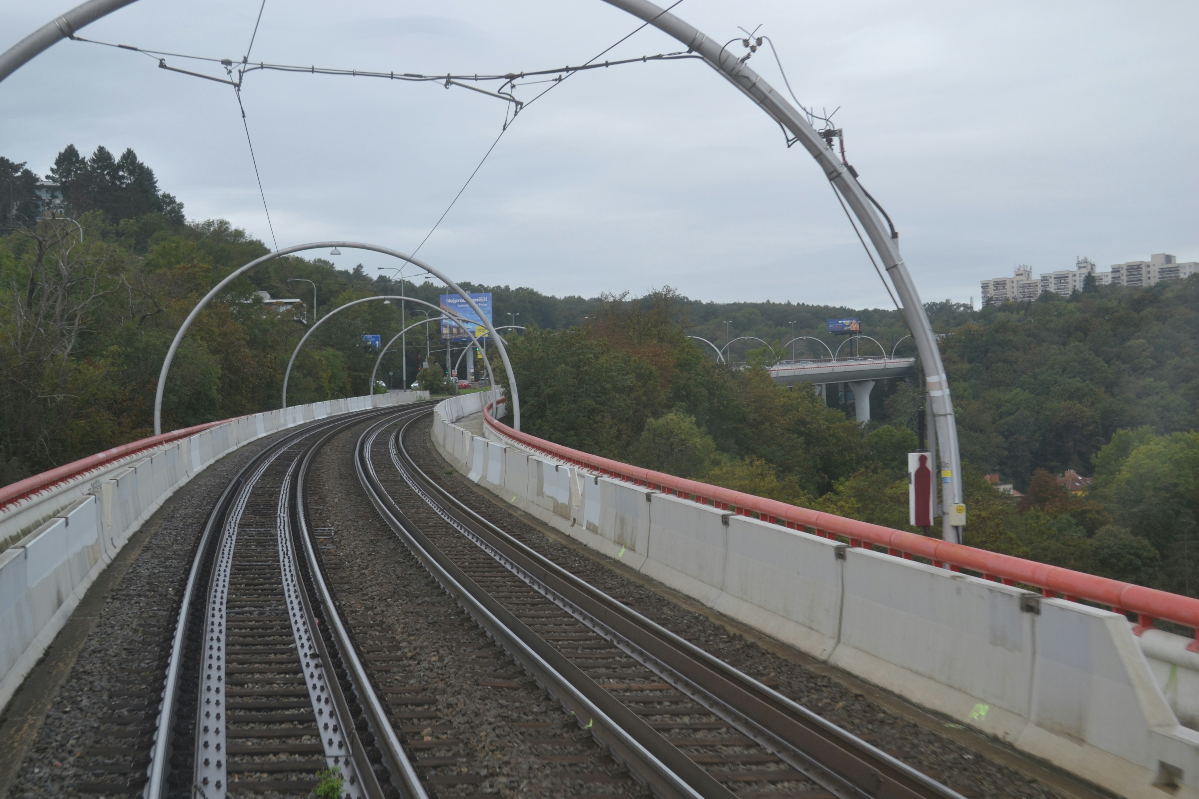 Train tracks winding through a lush landscape with modern infrastructure in the background.