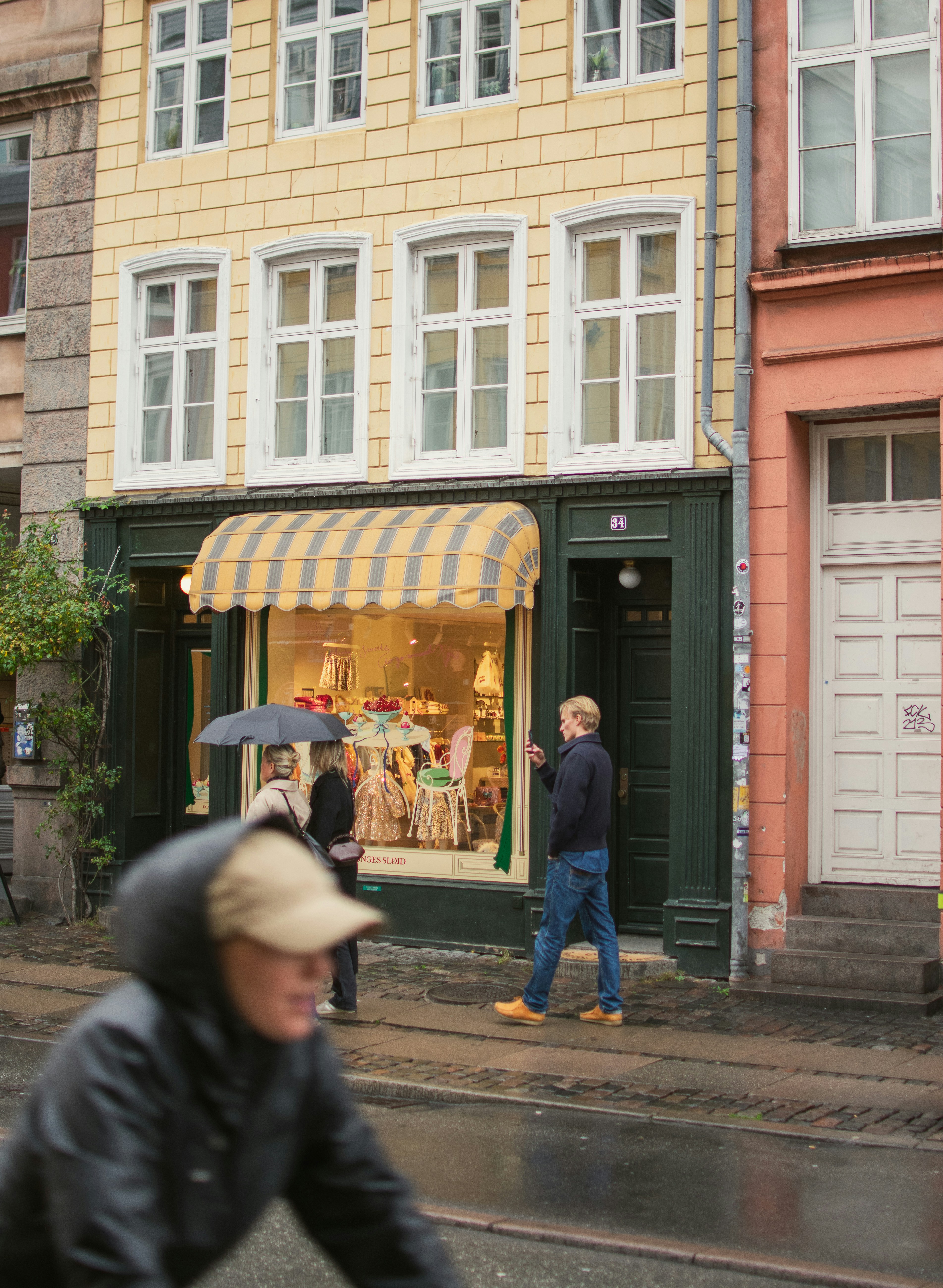 People walk past a shop on a rainy day.