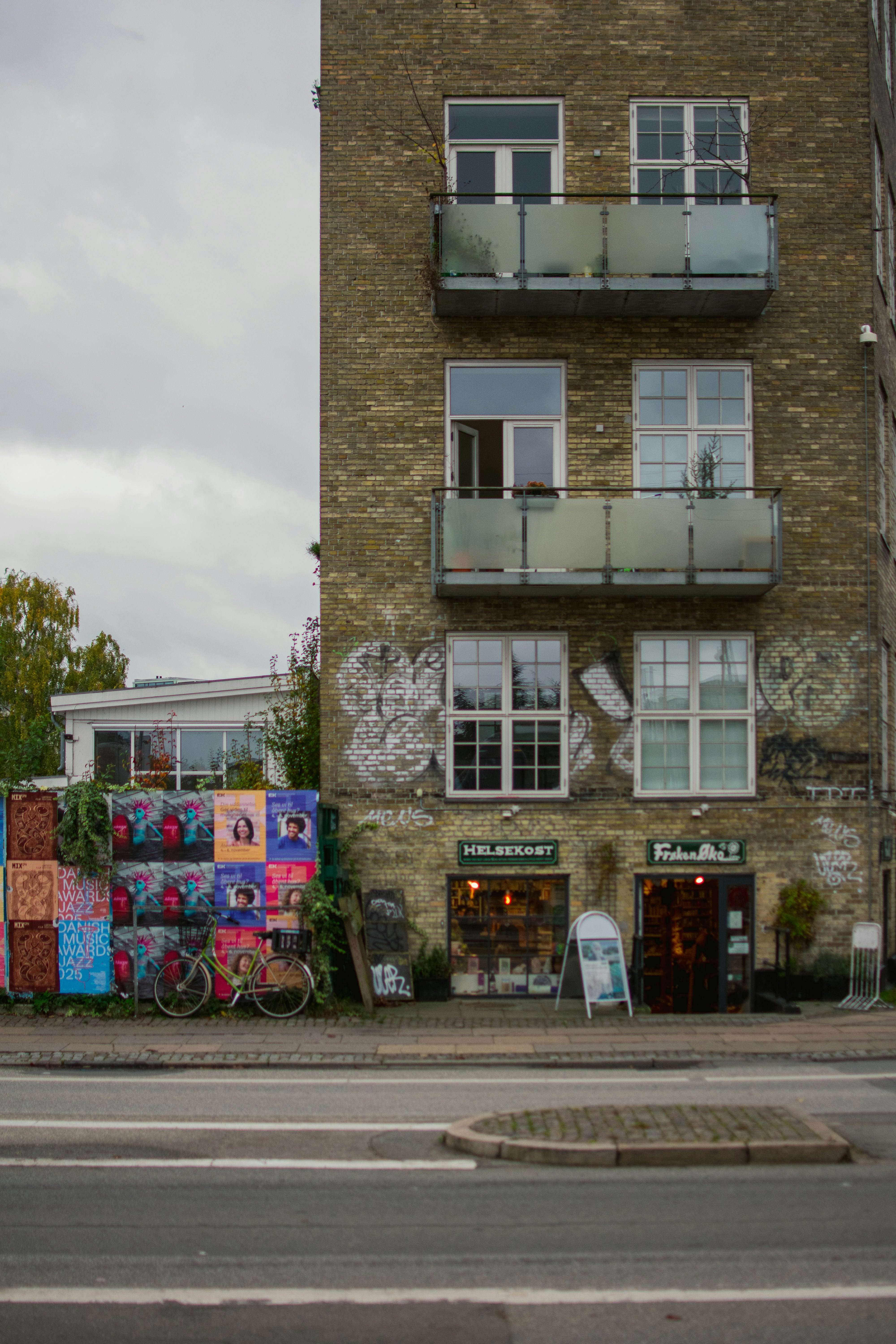Brick-Faced Urban Portrait: Glass Balconies Above a Graffiti-Laced Storefront