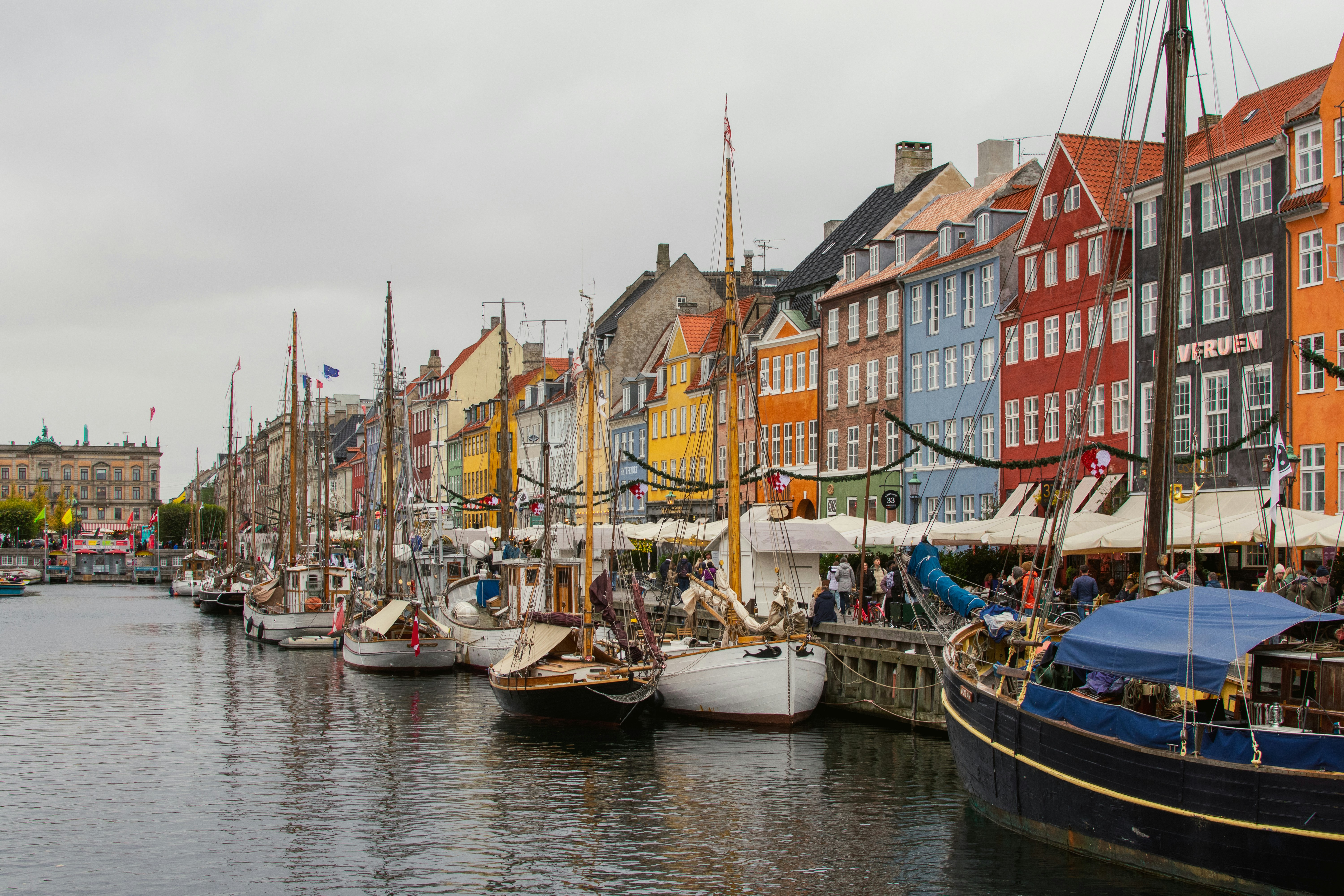 Vibrant row of historic buildings lining a bustling harbor, adorned with boats reflecting the charm of coastal life.