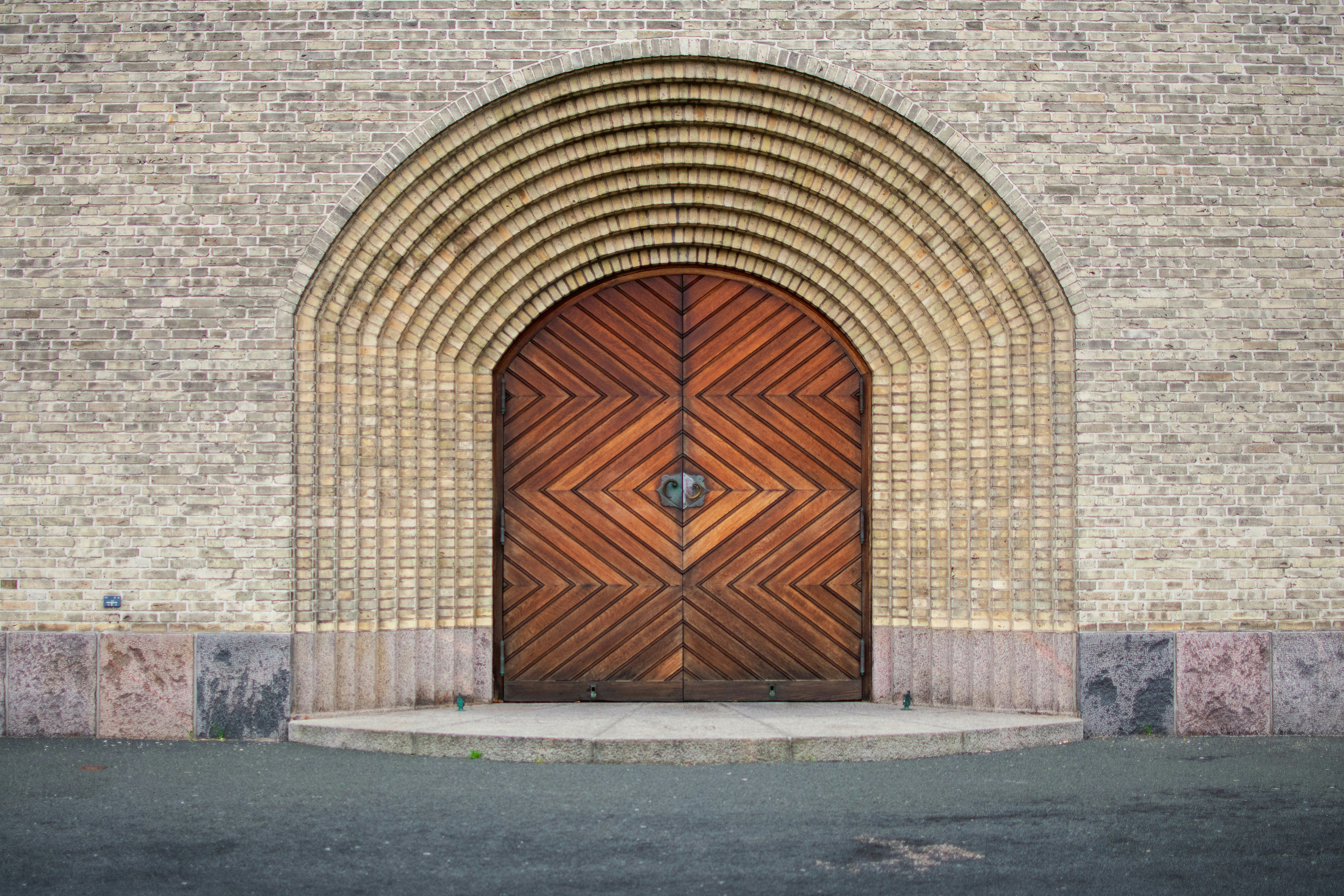 Arched wooden door set in a brick wall.
