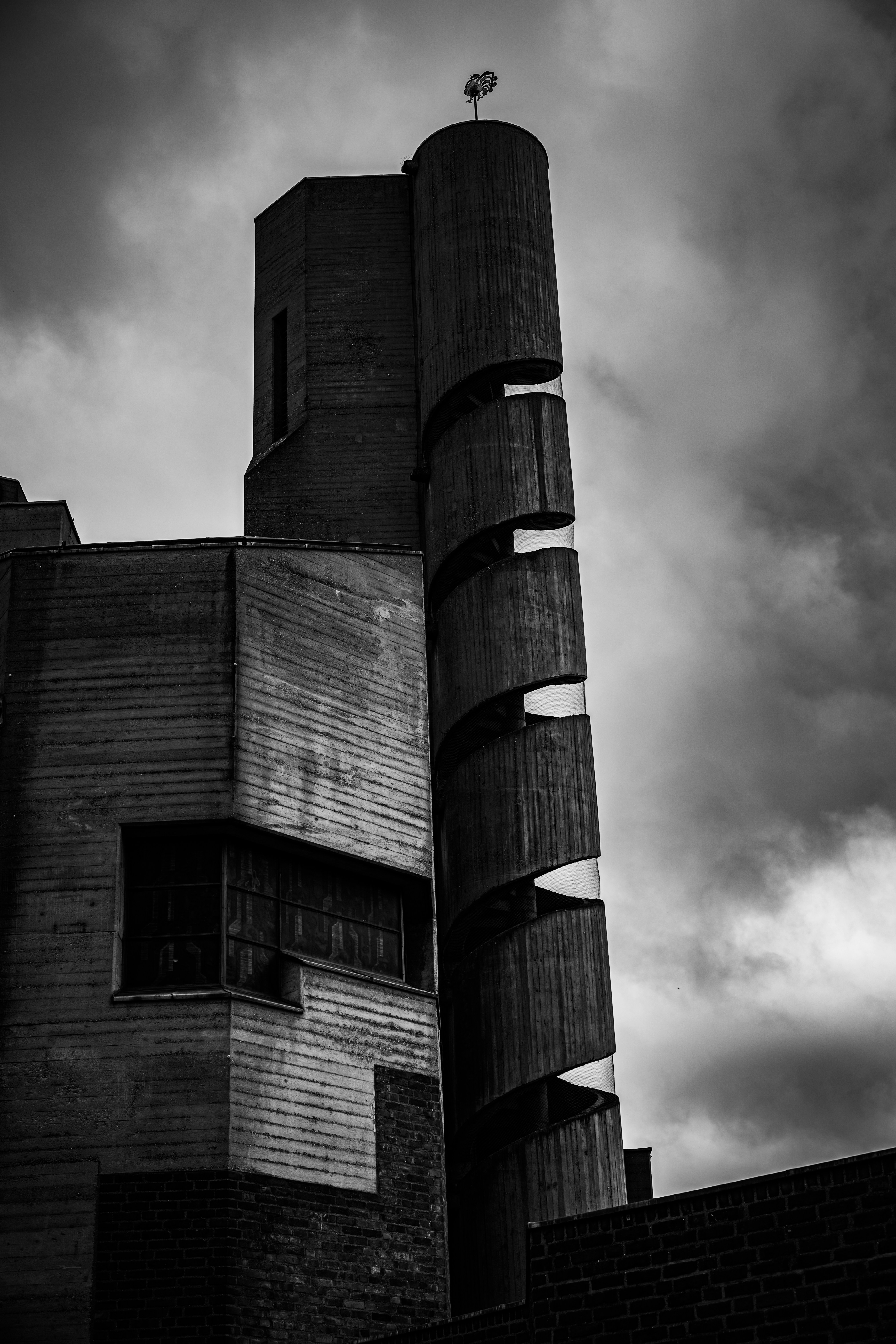 Brutalist Spiral: Concrete Chimney Rising into a Stormy Sky