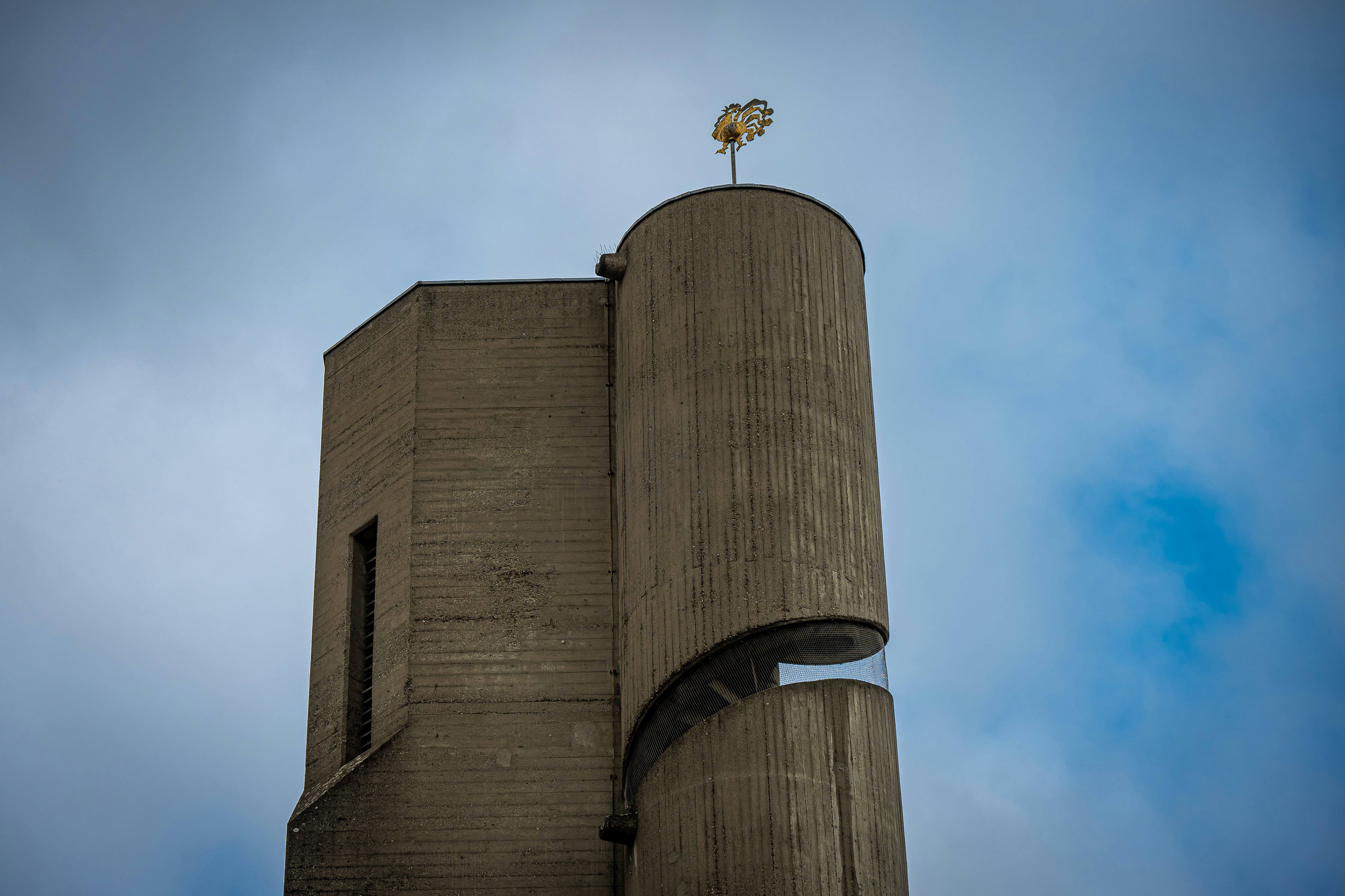 Rooster at the Summit: A Concrete Cylindrical Tower Reaching Toward the Sky