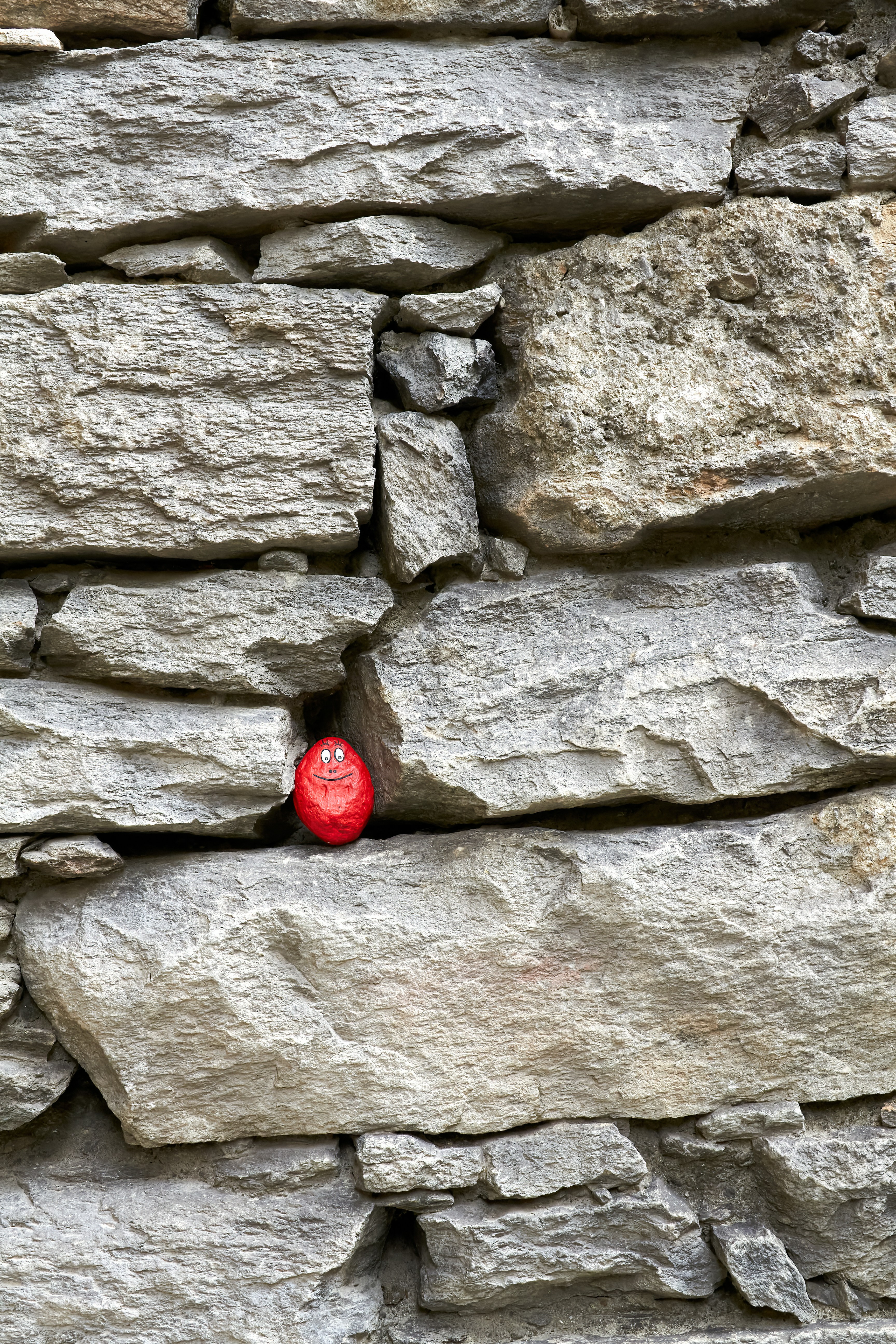 A small red object rests on a stone wall.