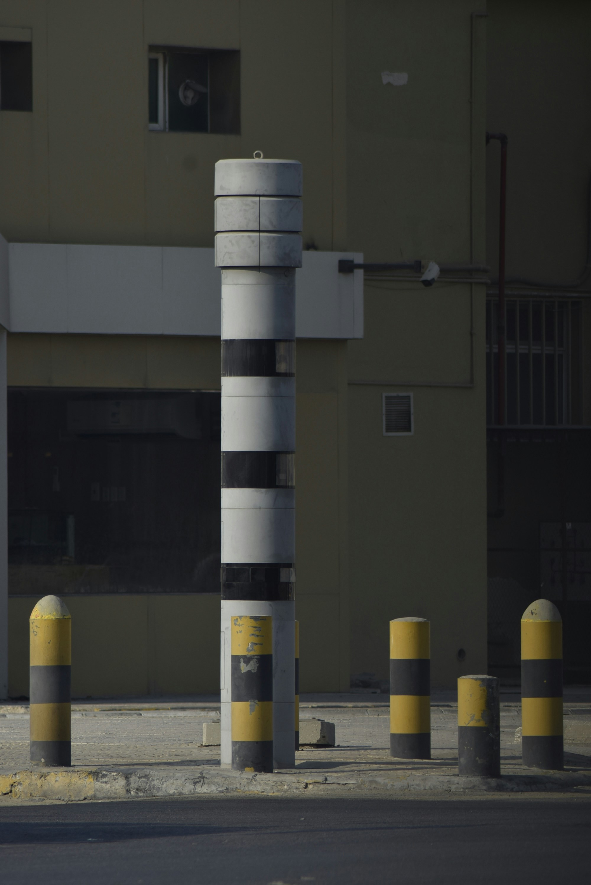 Vertical Stripe Sentinel: A Centered Pillar Among Urban Bollards