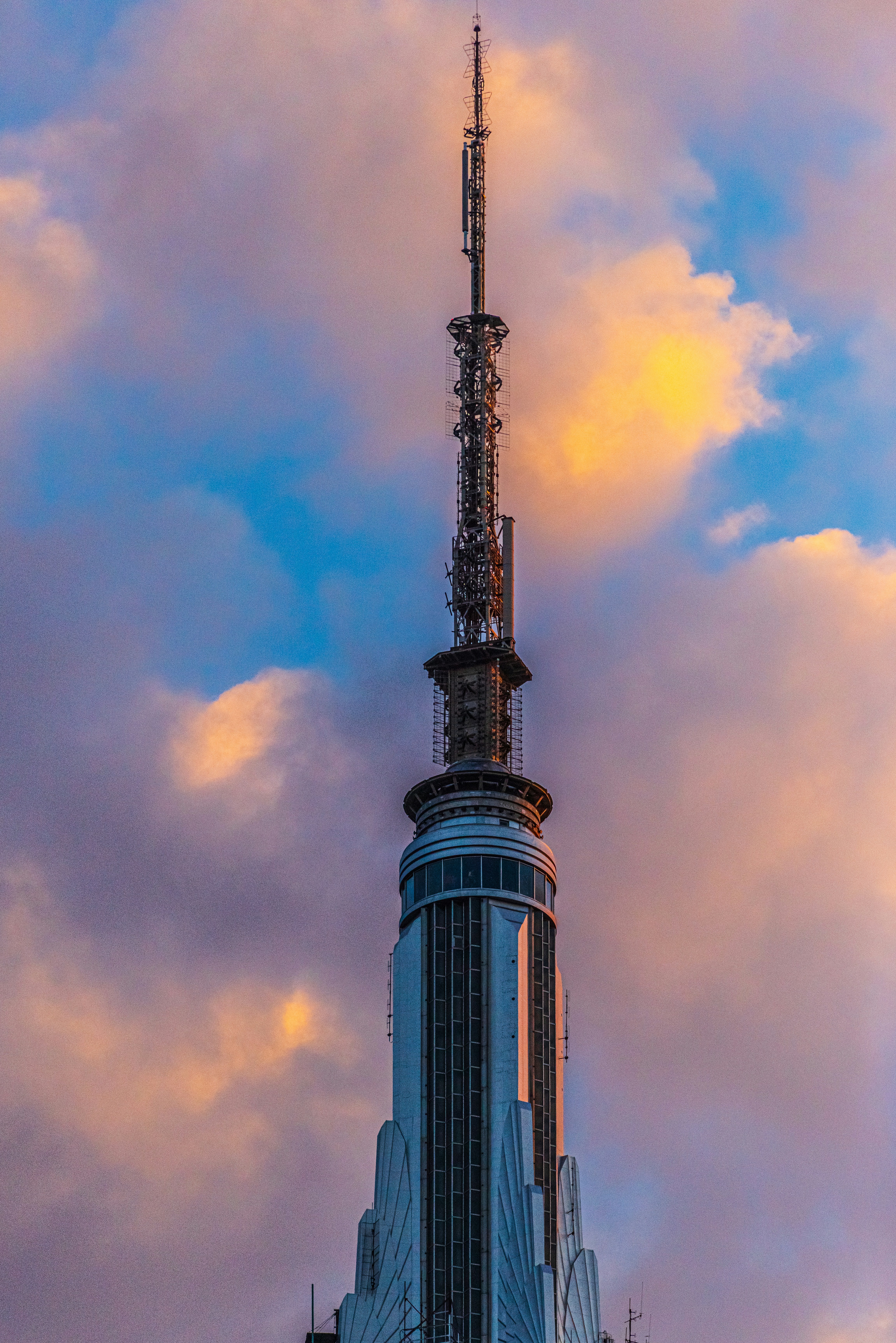 Empire State Building at sunset. | Empire state building spire against colorful sunset clouds