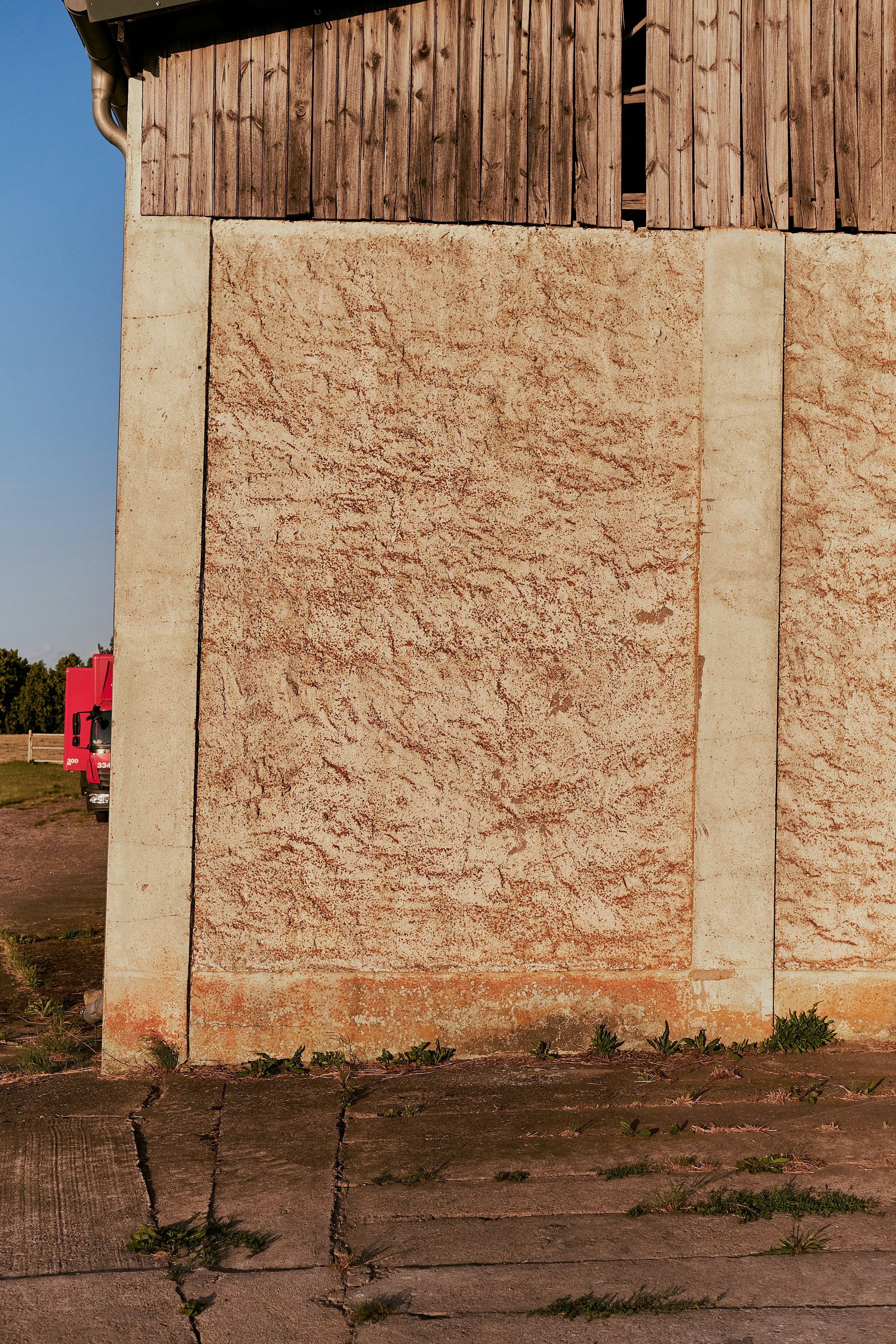 Sunlit seam: weathered plaster and a hint of red in an industrial facade