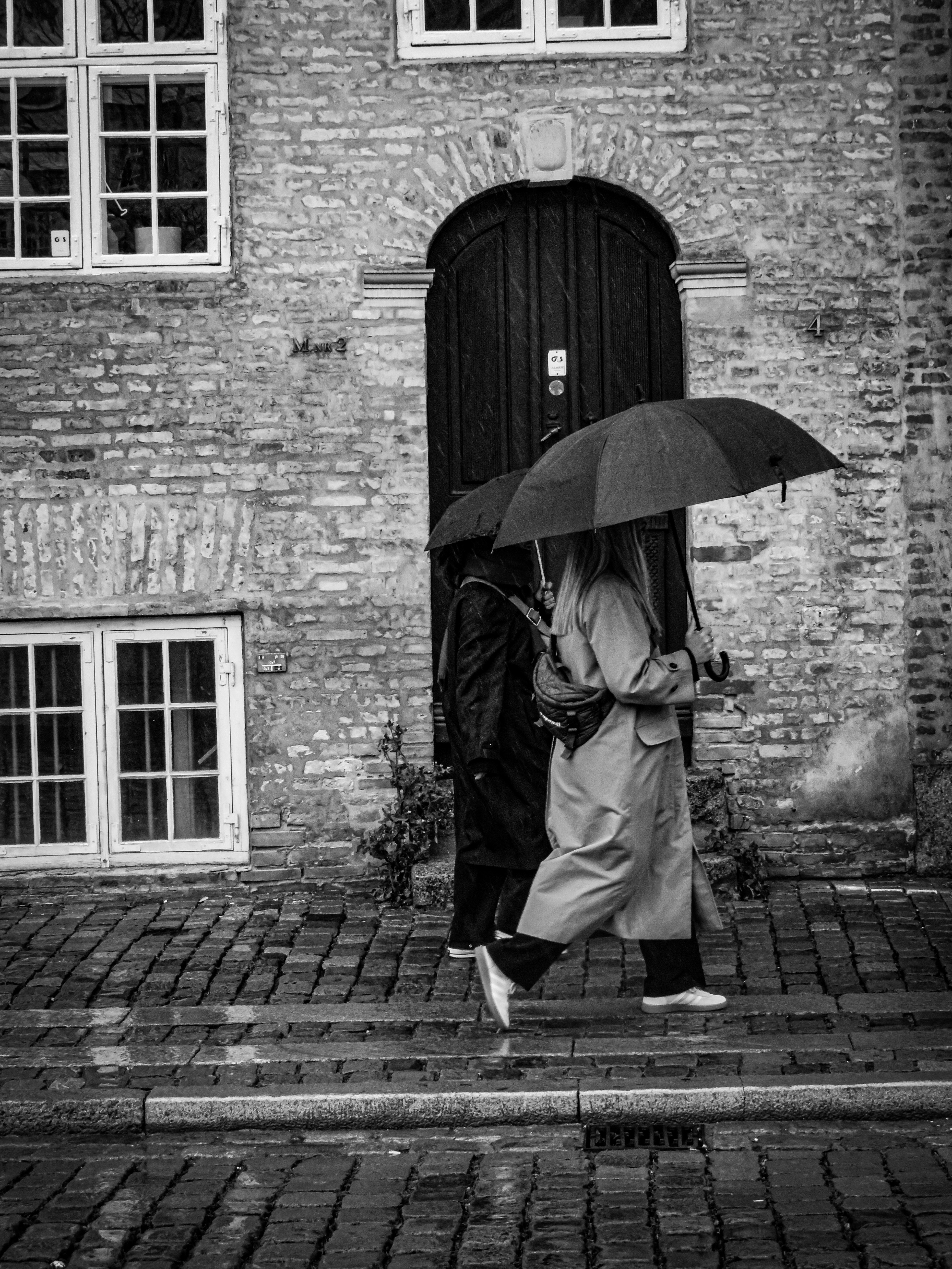 Two people walk under umbrellas on a rainy day.