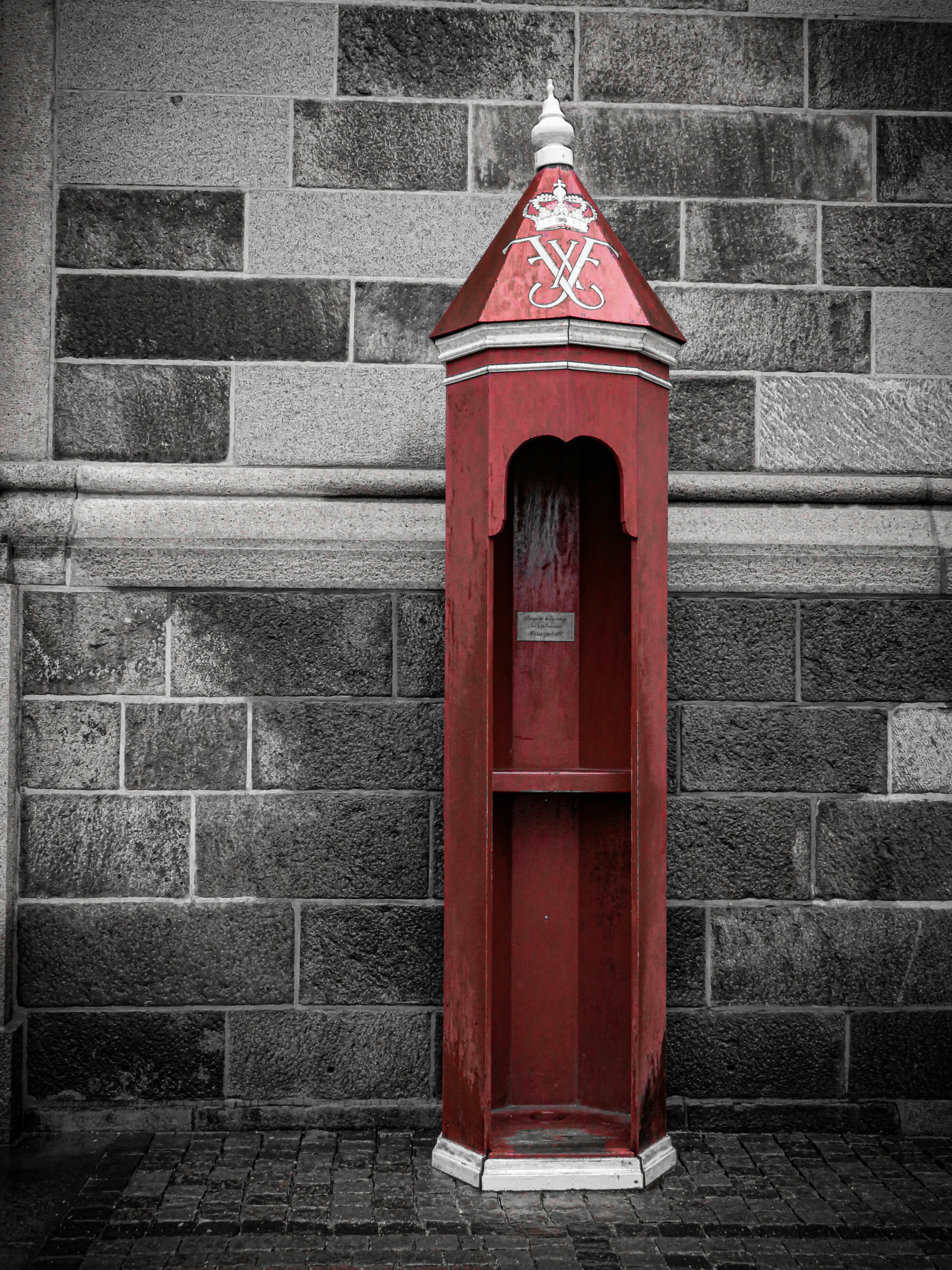 A red british telephone box against a brick wall