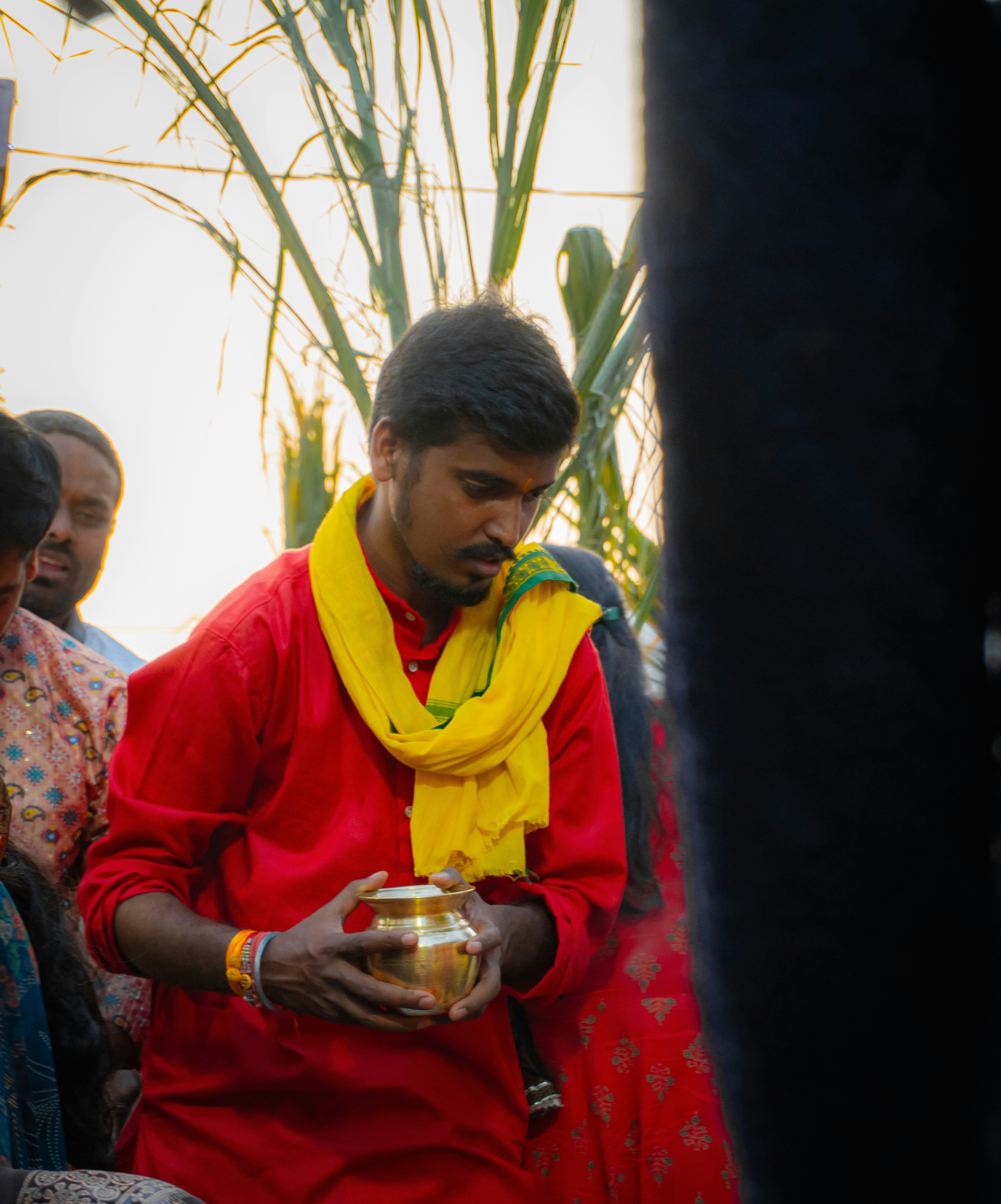 Brass Vessel under Dusk: A Youth in Red Kurta at a Festival