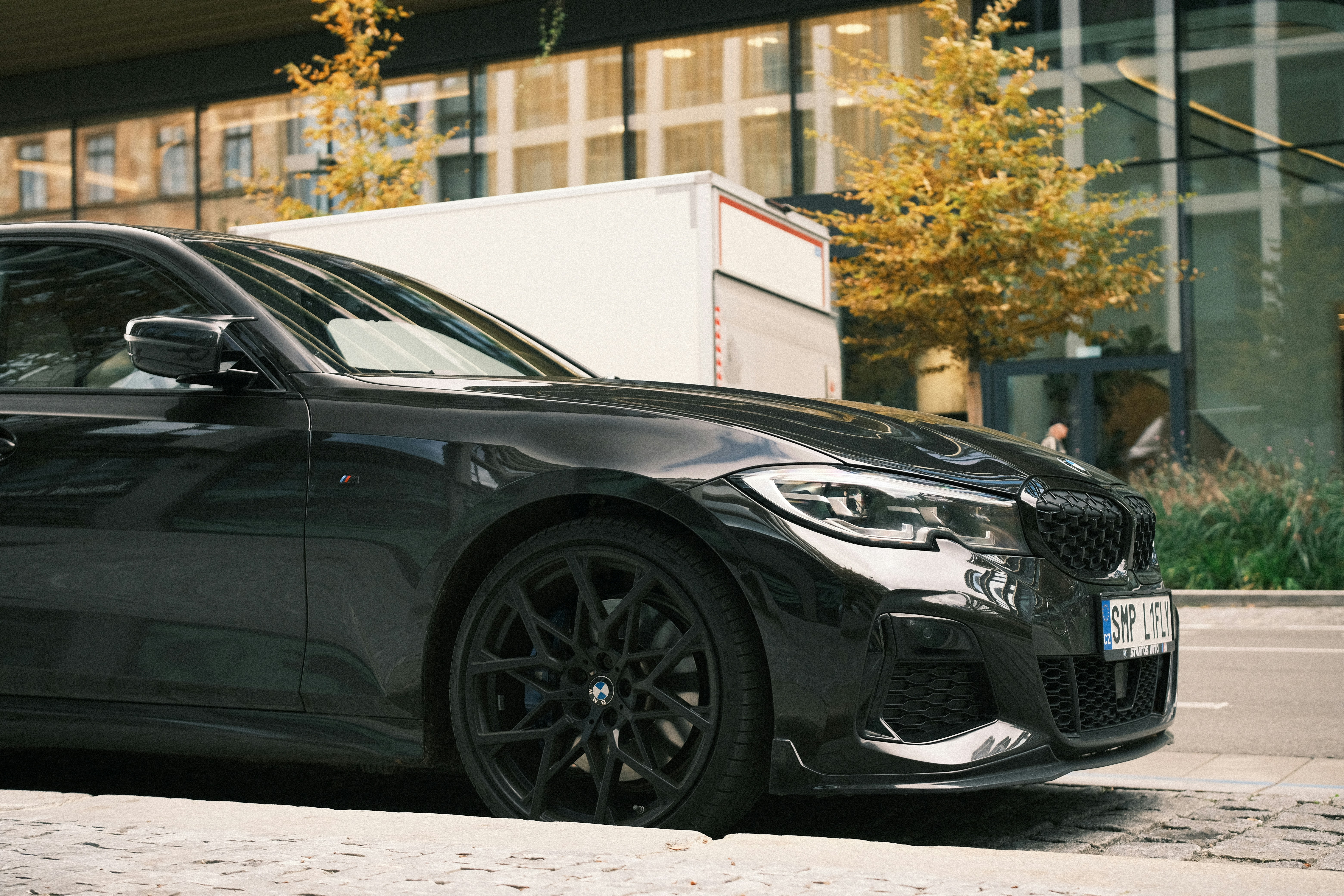 Sleek black BMW parked in an urban setting, showcasing its stylish design against a backdrop of contemporary architecture and greenery.