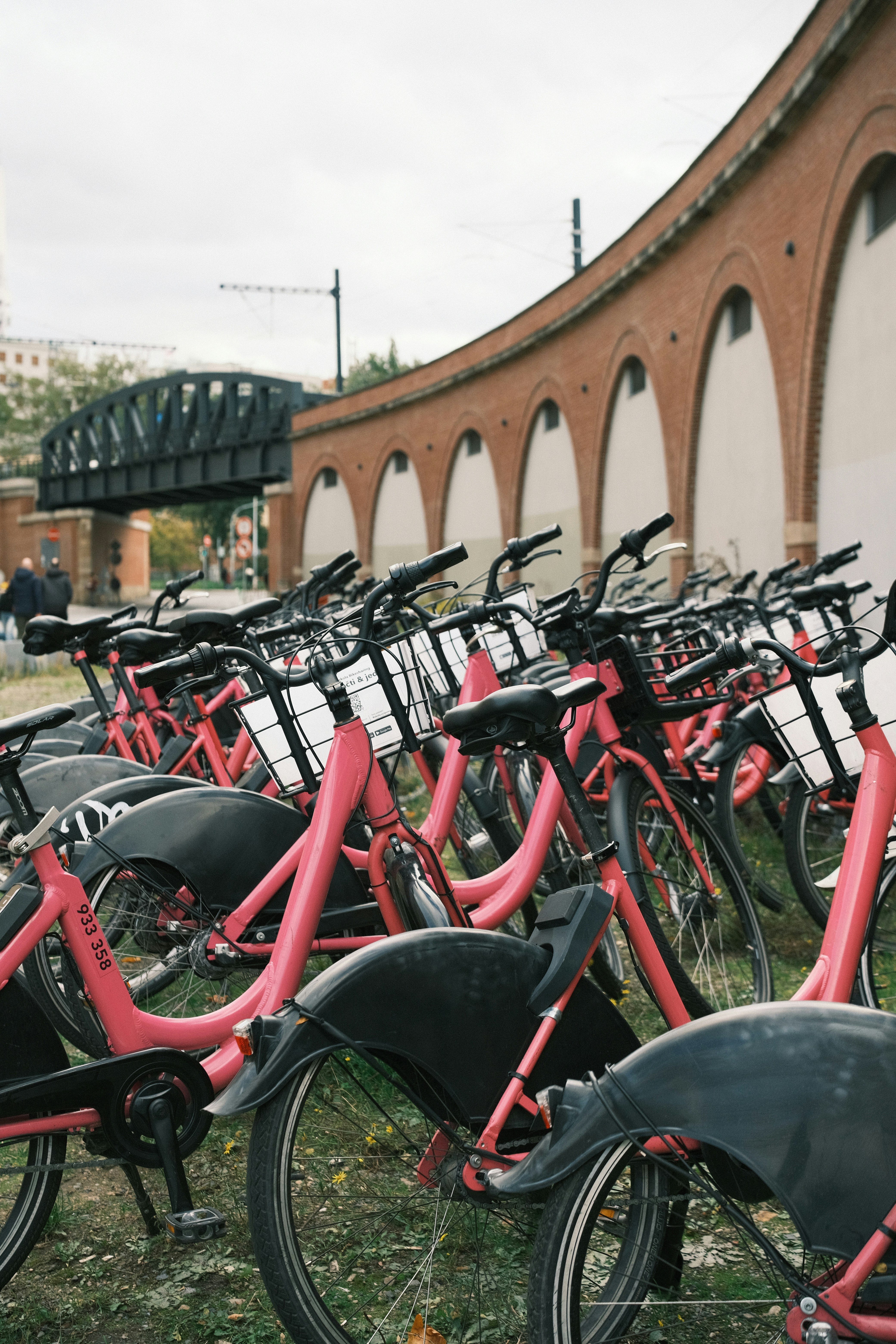 Pink bikes parked near brick wall | Row of pink bicycles parked outdoors near brick building.