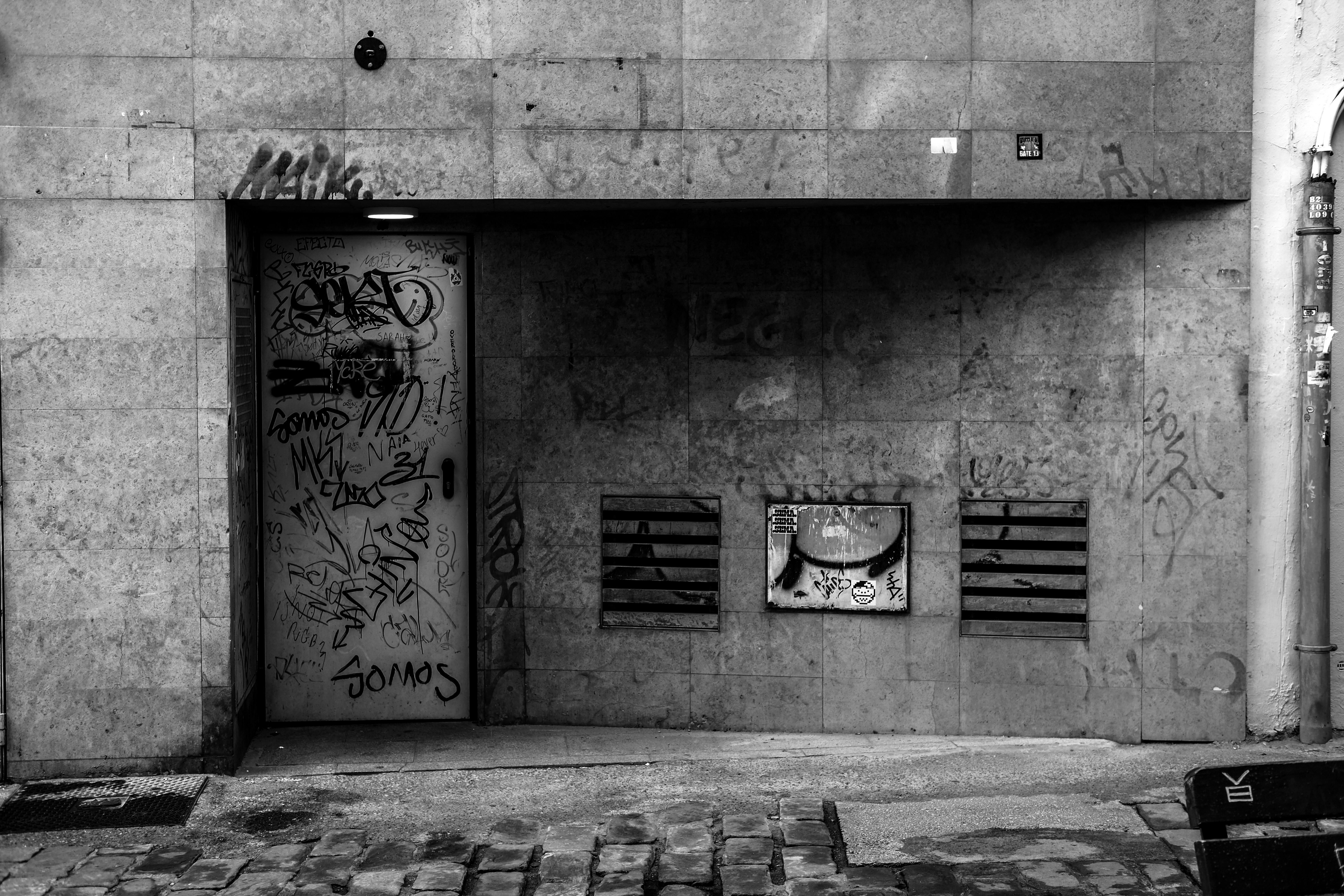 A weathered door adorned with graffiti, set against a textured wall, revealing the raw essence of urban life.
