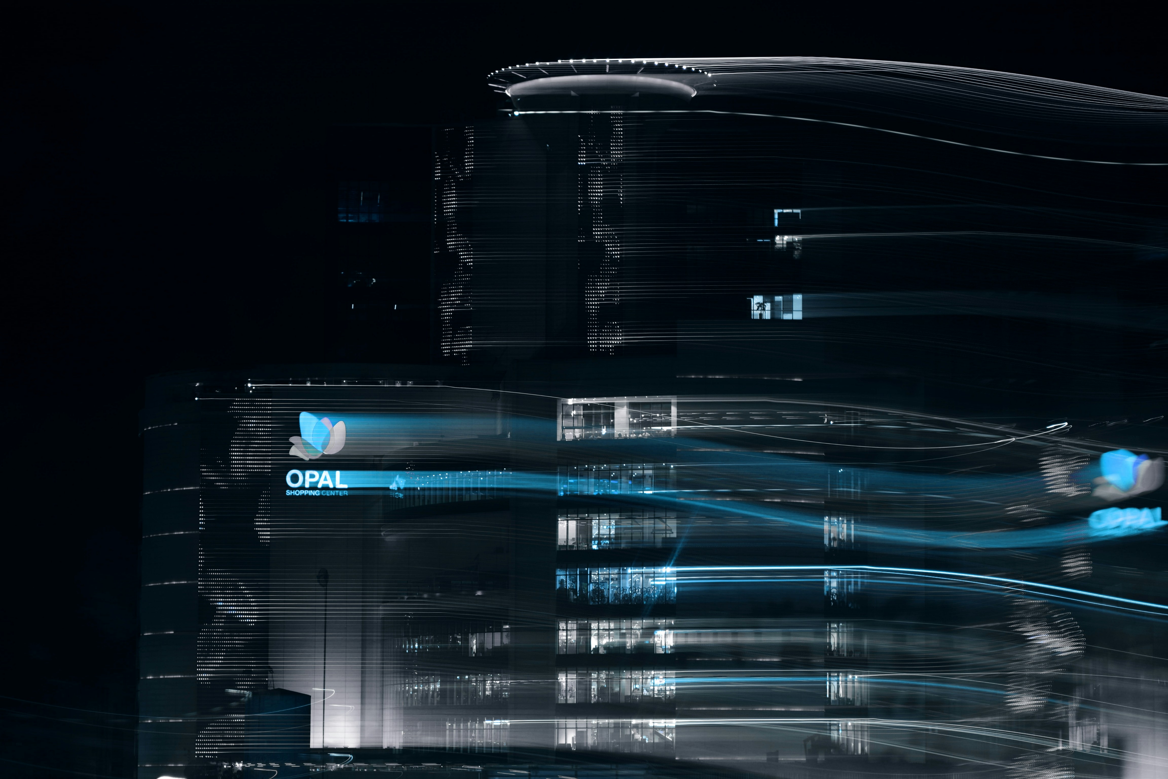 A modern building illuminated by dynamic blue lights, showcasing a blend of architecture and motion blur effects at night.