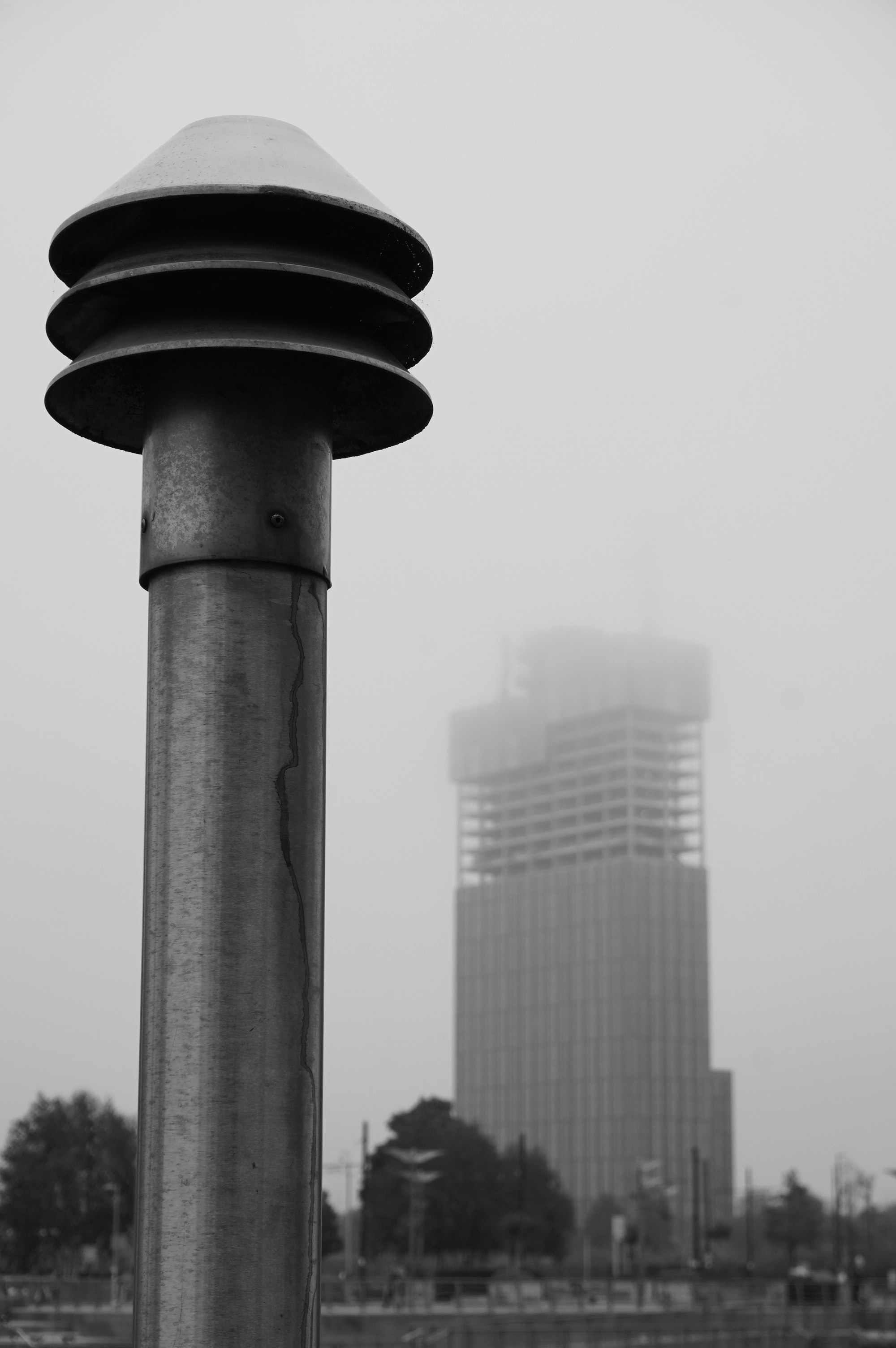Lamppost in the Fog: A Quiet Urban Pole Reaching Toward a Distant Tower