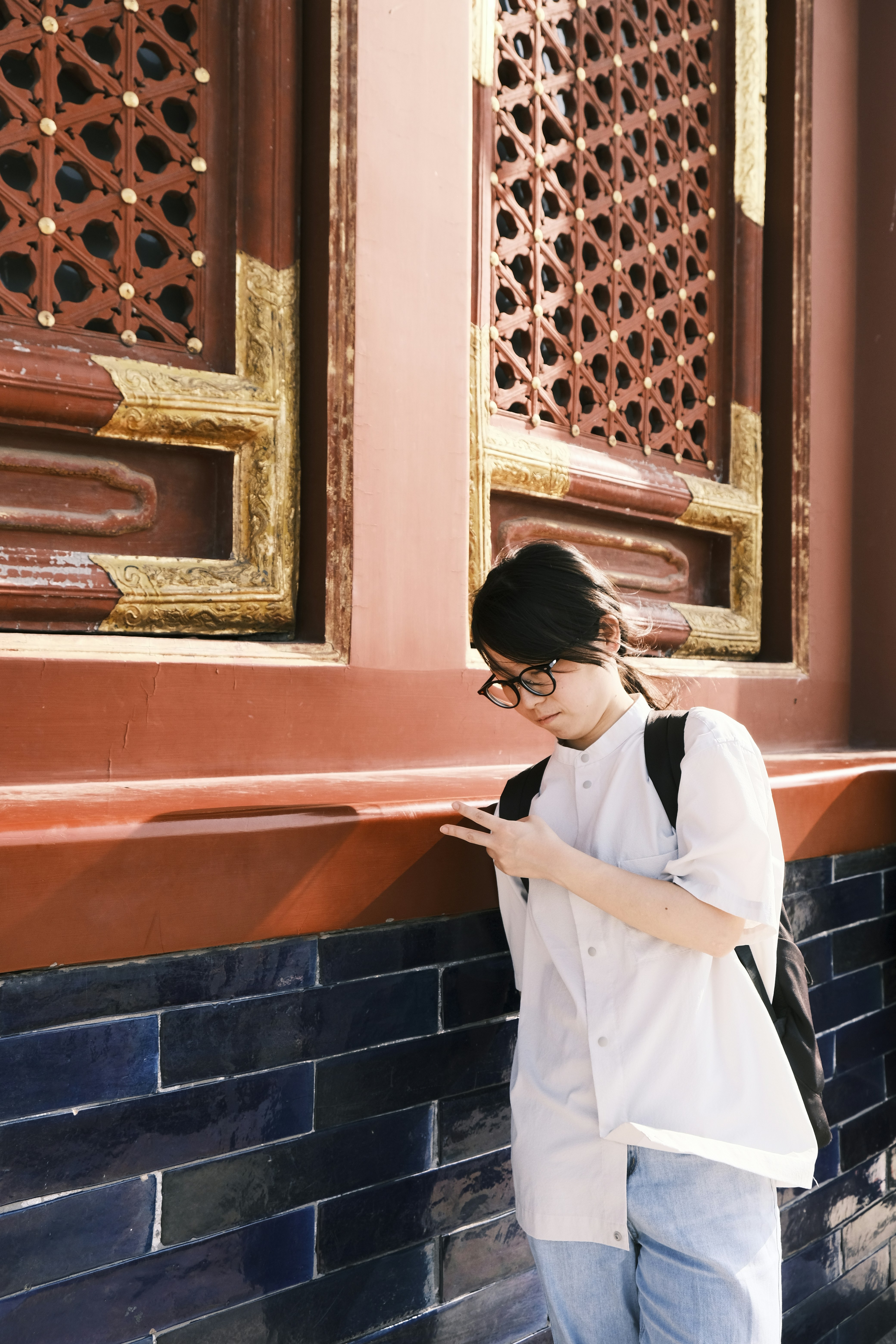 Quiet Focus at the Red Wall: A Student in White by Ornate Lattice Windows