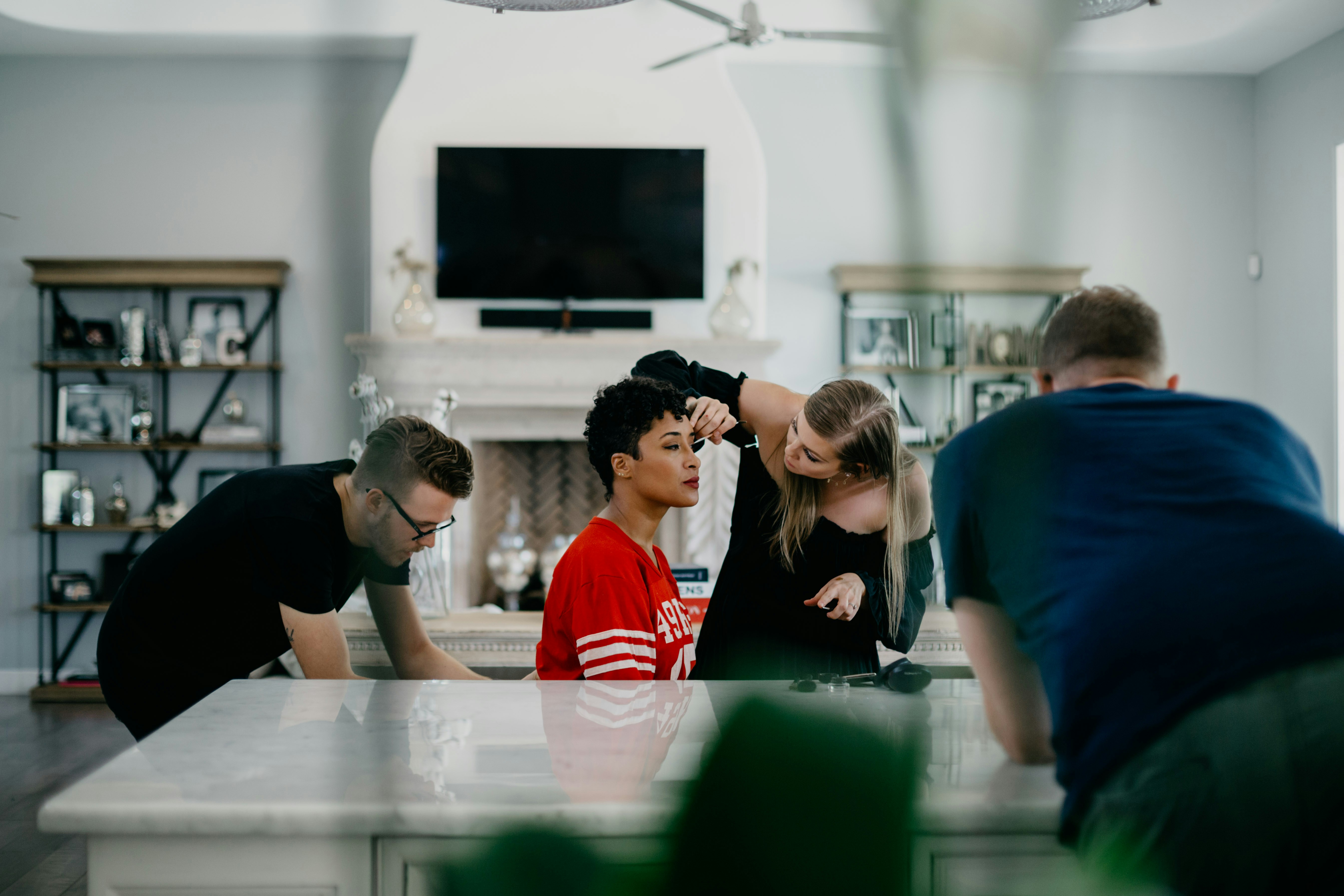 A group of professionals collaborates to prepare a model for a photoshoot, showcasing the artistry of makeup application in a modern setting.