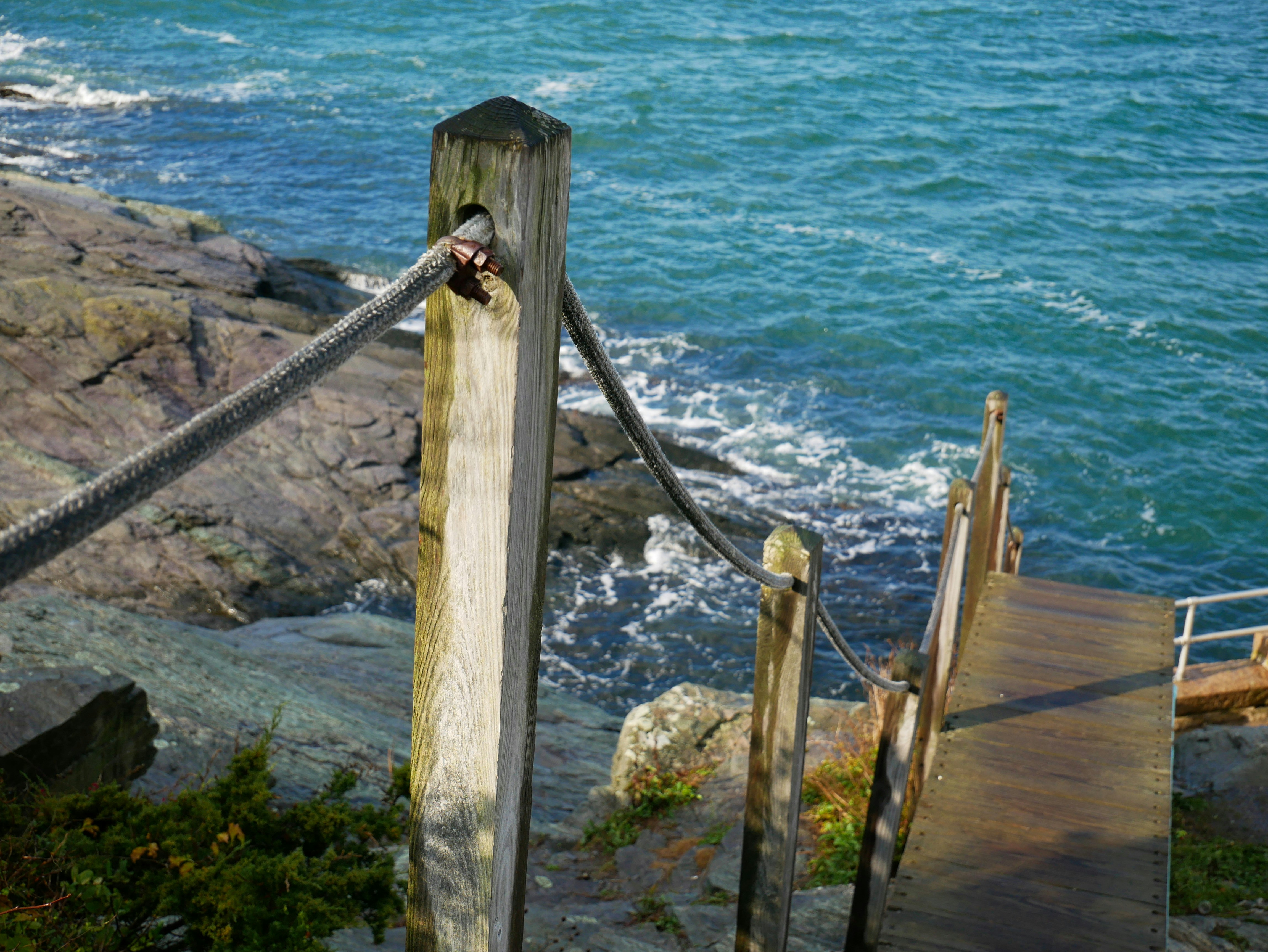 Wooden stairs lead down to a rocky coastline and ocean.