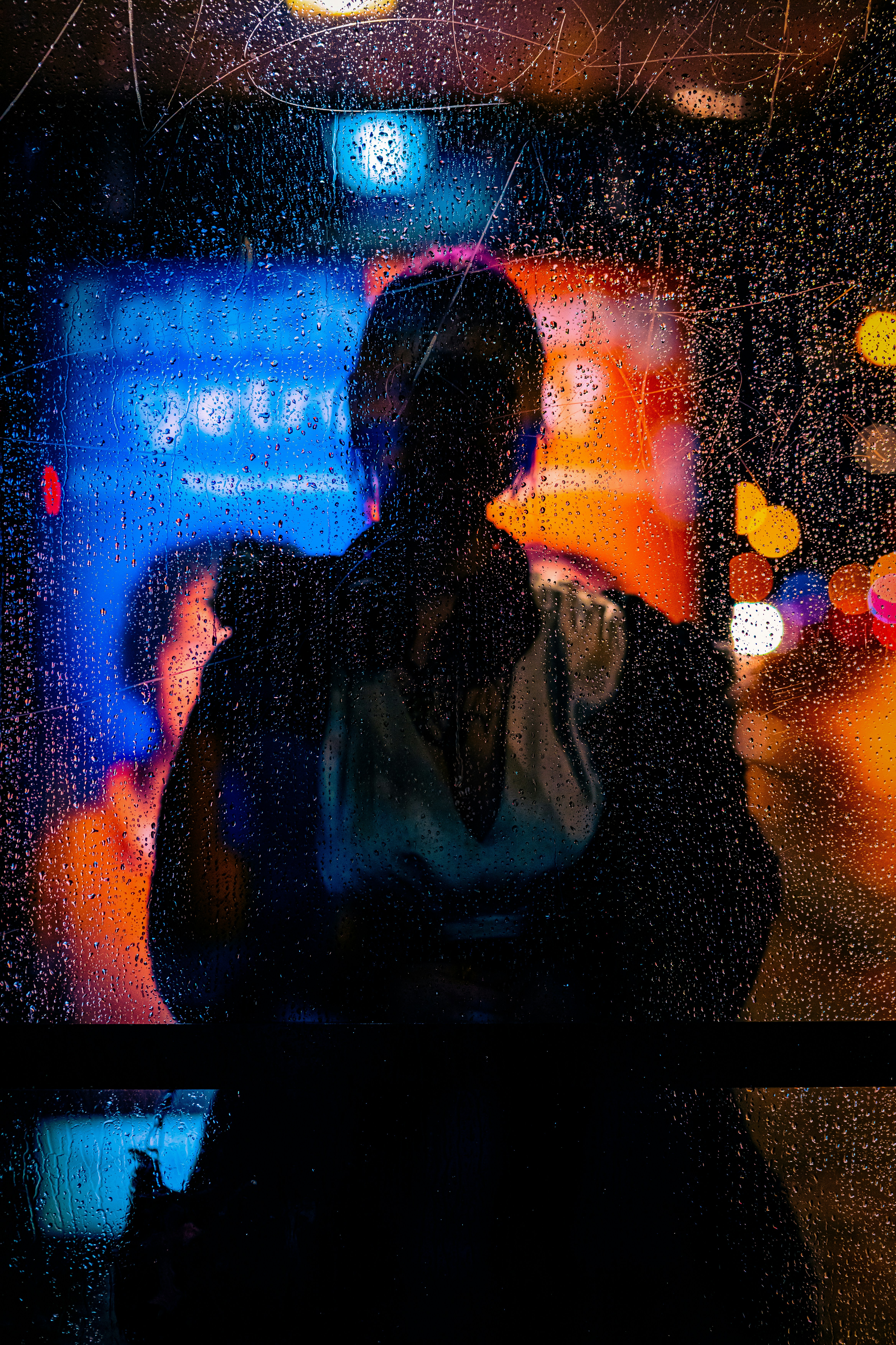 Neon Veil: Nighttime Silhouette Behind a Rain-Soaked Window