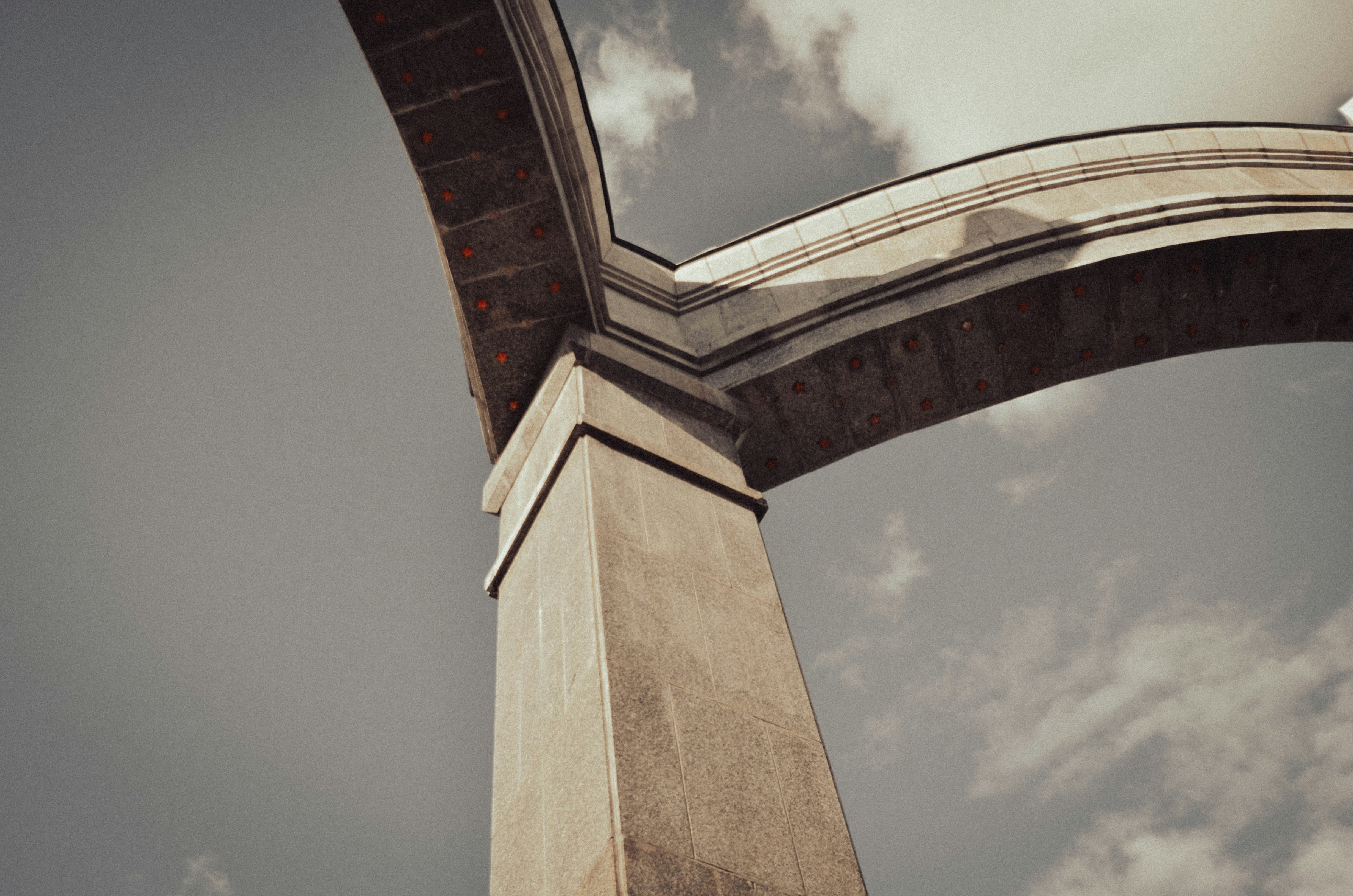 Close-up view of a concrete archway showcasing intricate design and texture against a cloudy sky.