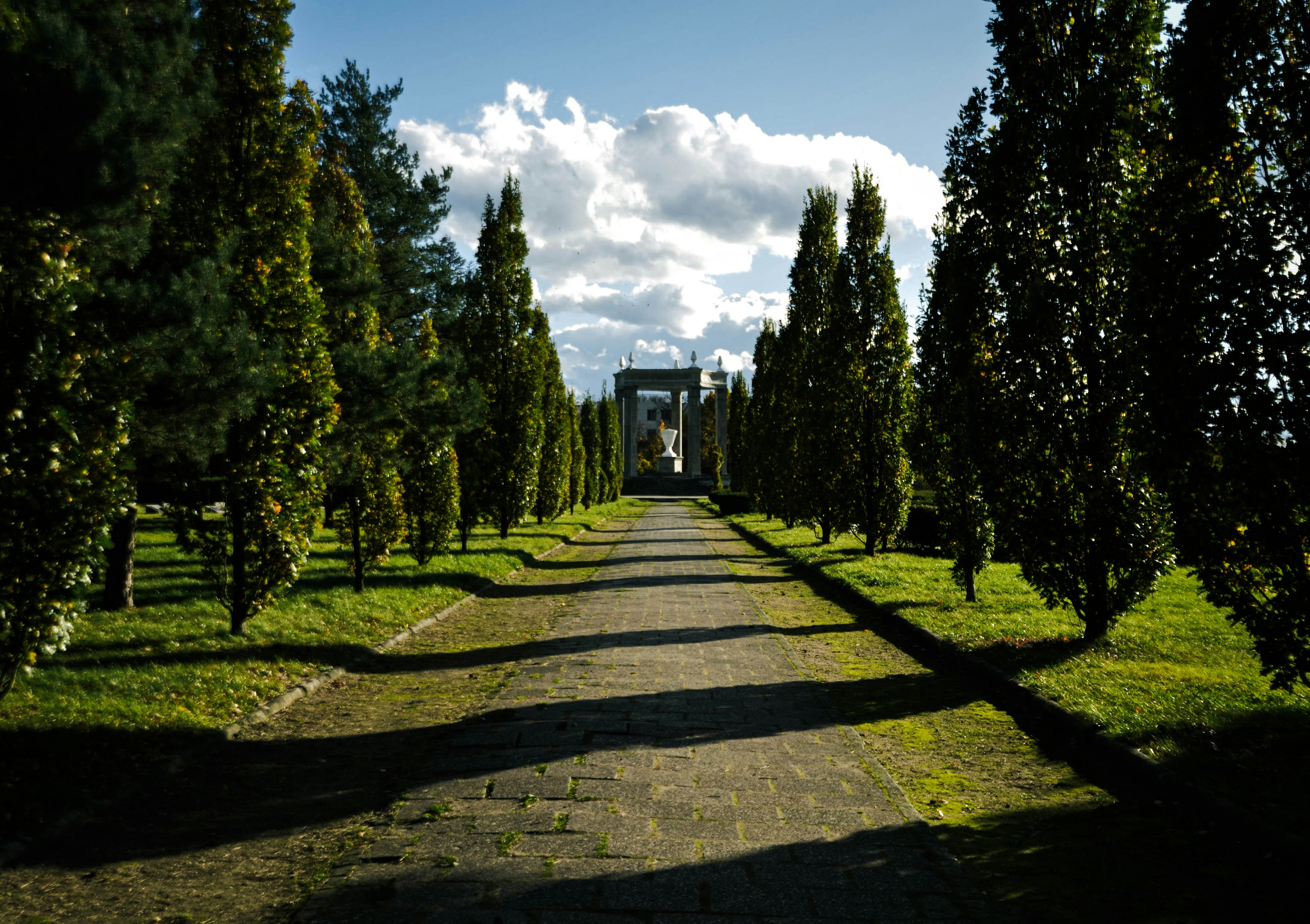 A tree-lined path leading to a distant structure.