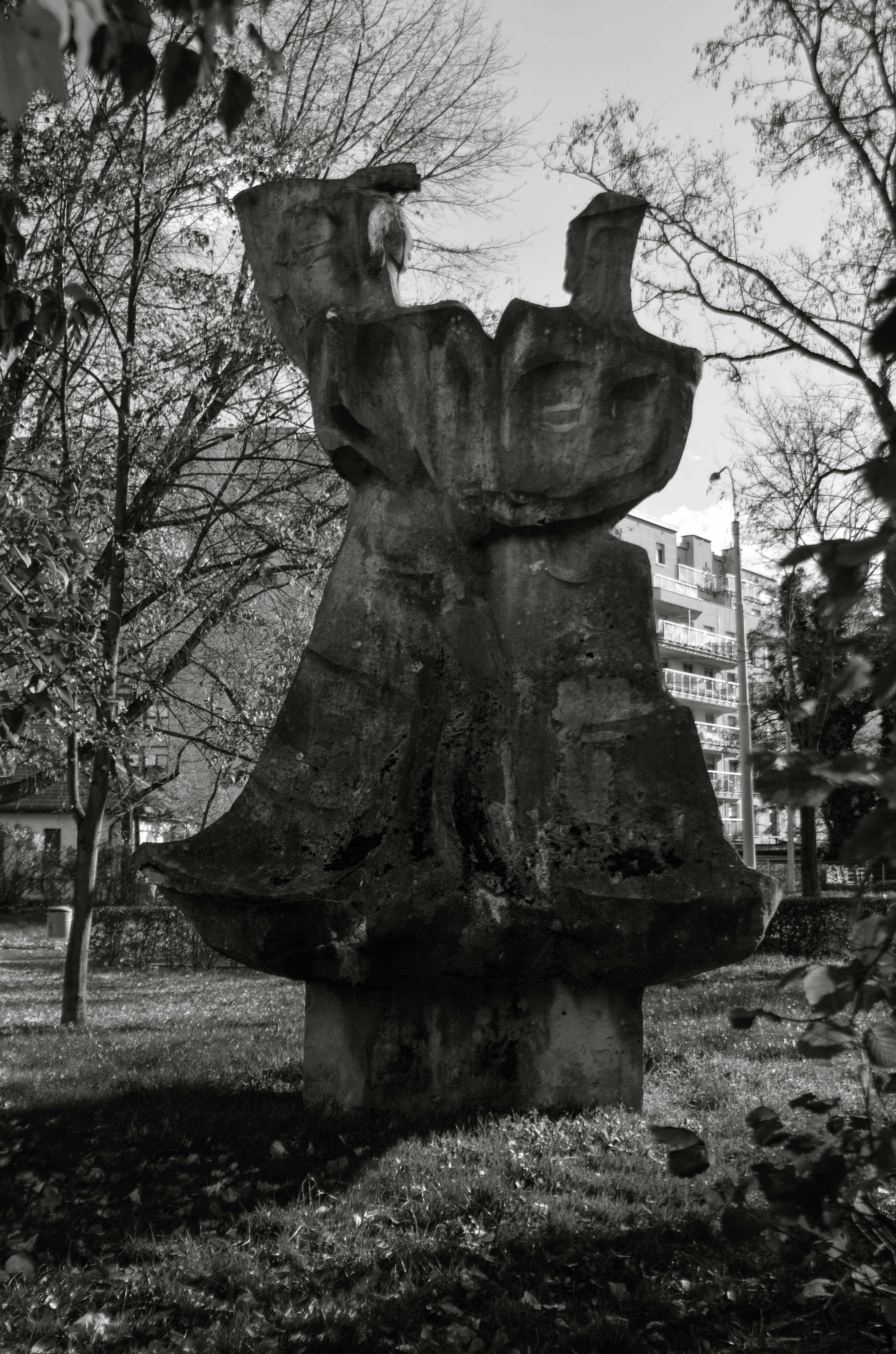 Stone Guardian Amid Bare Trees and Urban Backdrop