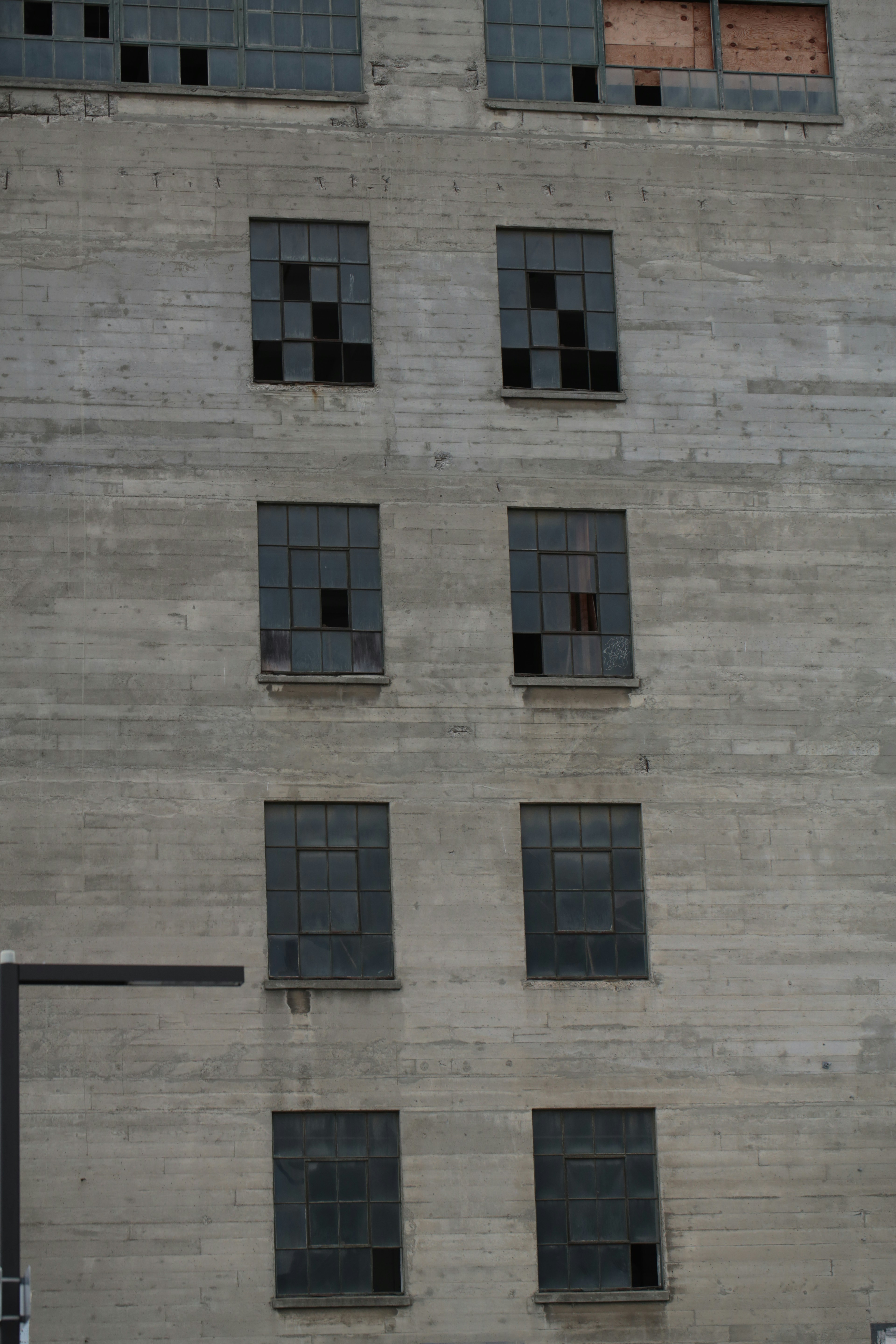 Abandoned building facade featuring a series of broken windows against a weathered concrete backdrop.