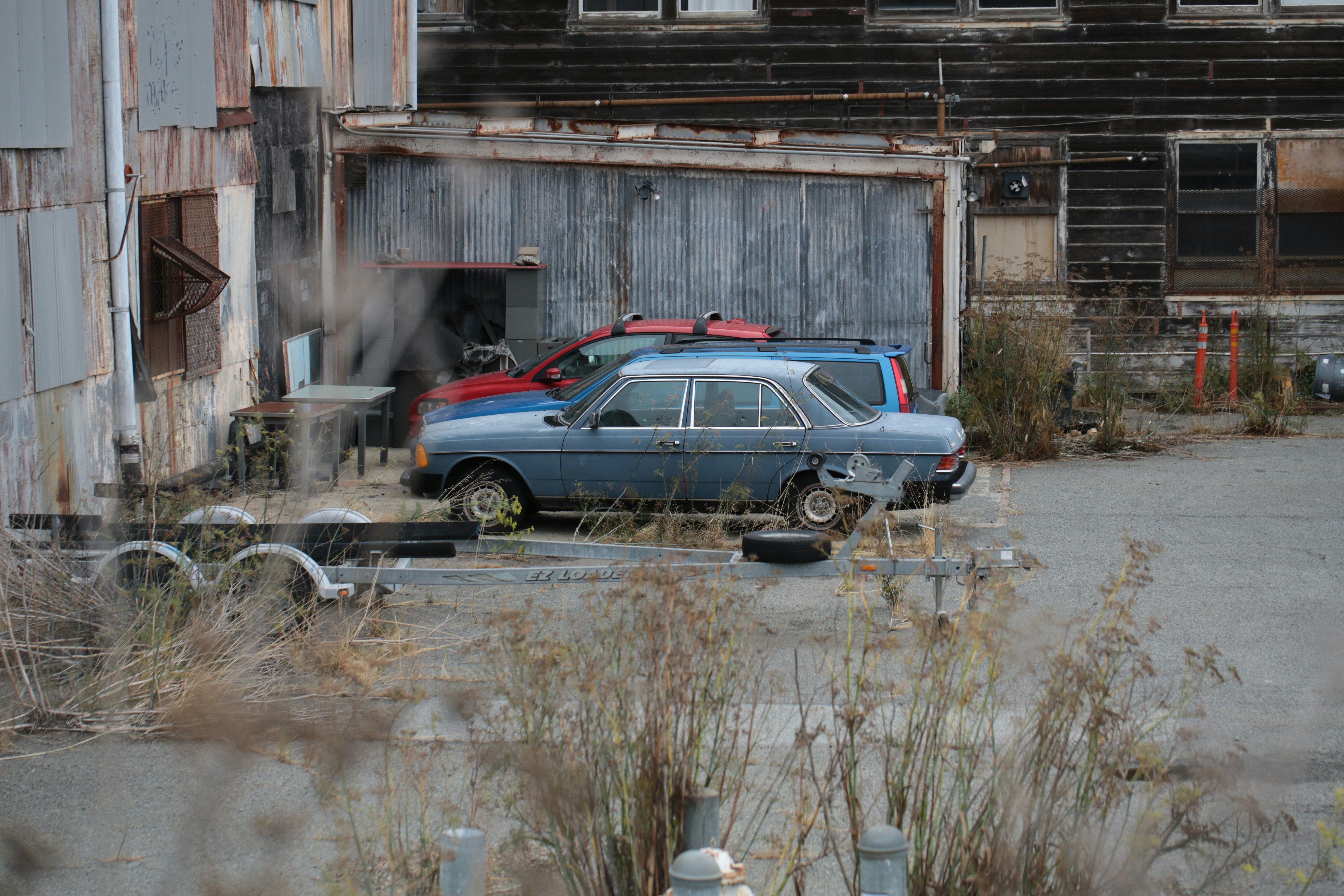 Blue Coupe in a Rusted Yard: Smoke, Silence, and Decay