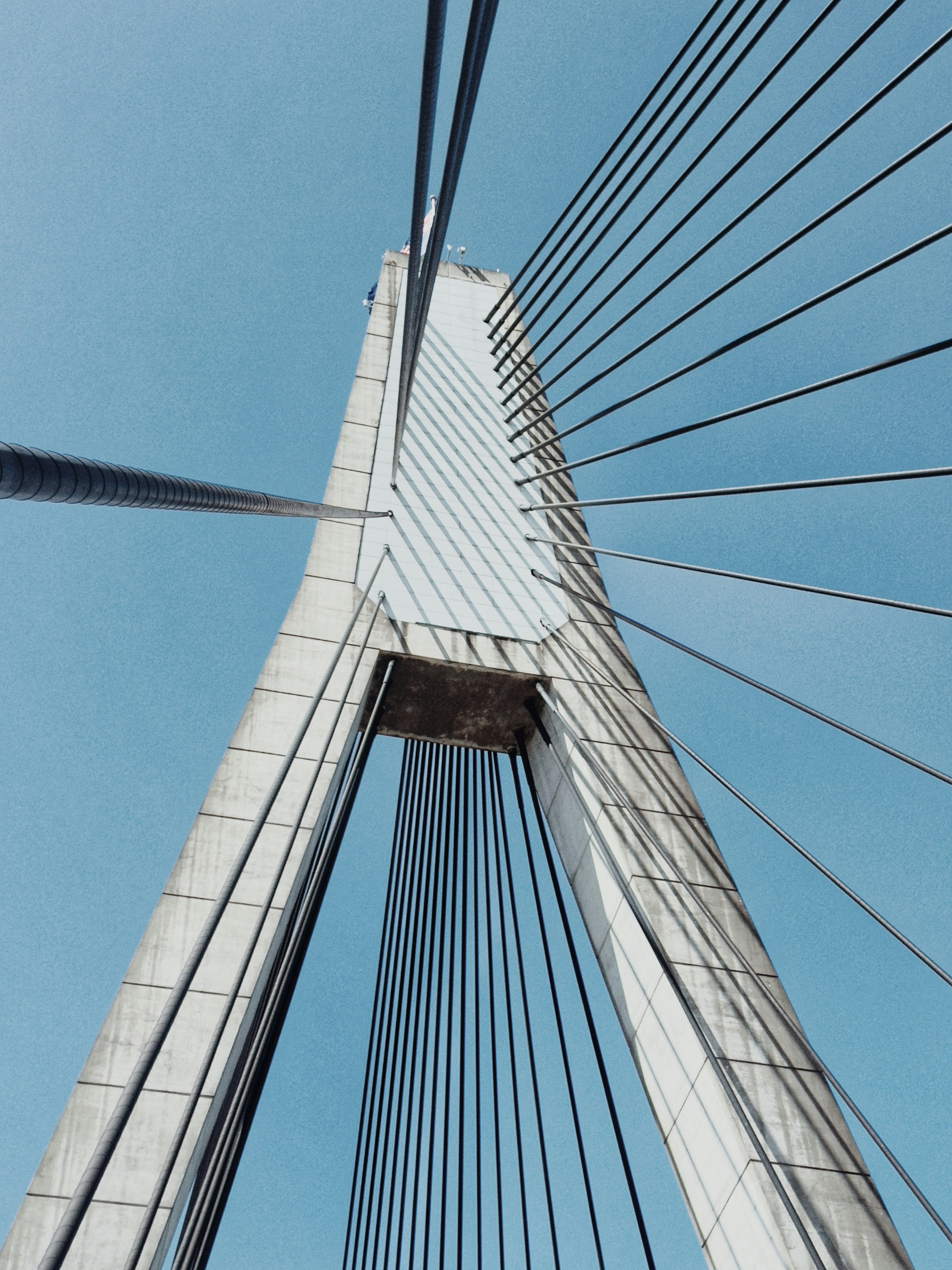 Modern suspension bridge tower against clear blue sky.
